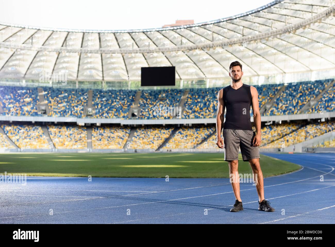 handsome young sportsman on running track at stadium Stock Photo - Alamy