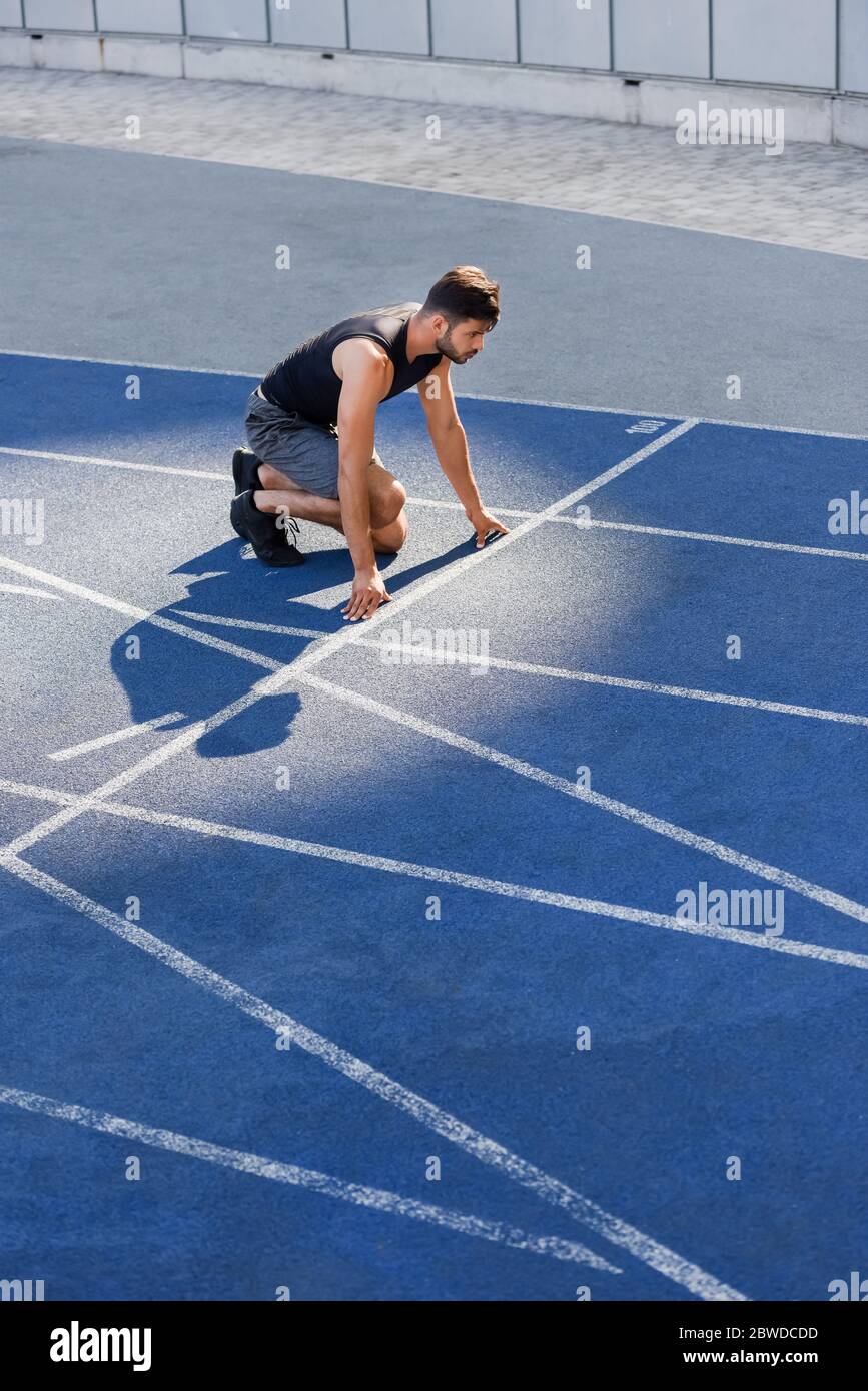 handsome runner in start position on running track at stadium Stock ...