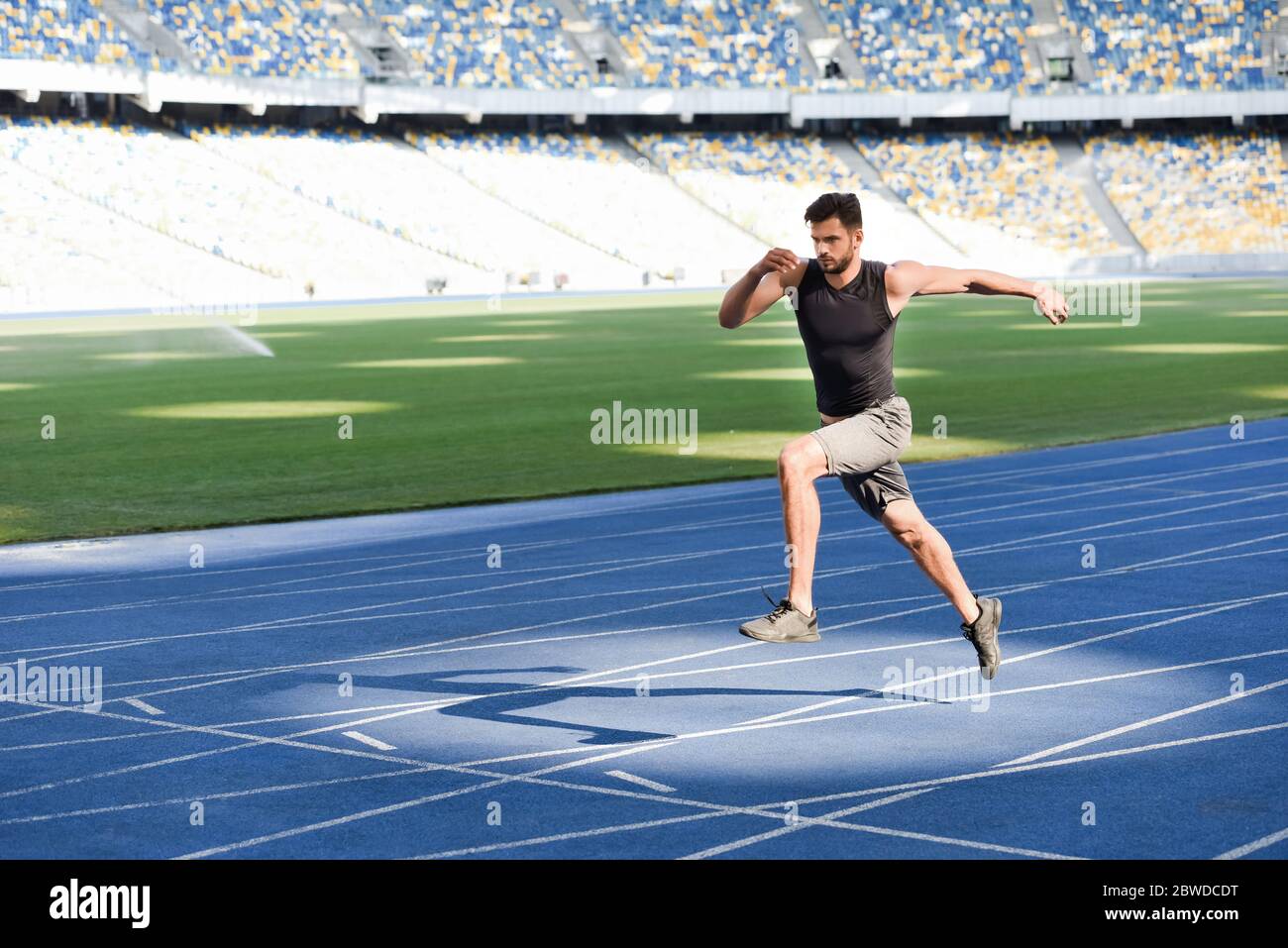 fast handsome runner exercising on running track at stadium Stock Photo ...