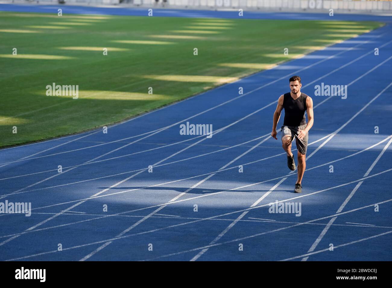 fast handsome runner exercising on running track at stadium Stock Photo ...