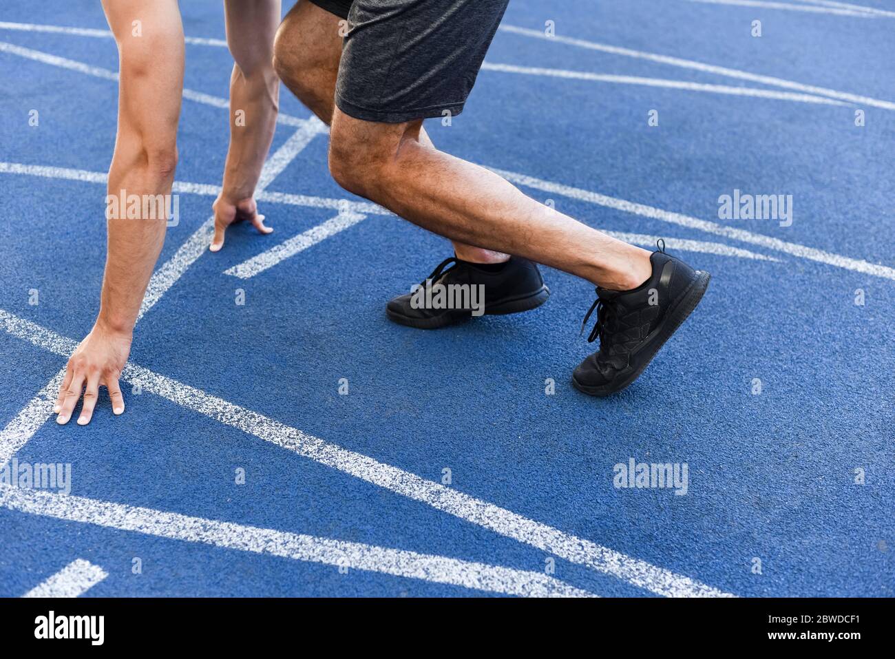 cropped view of runner in start position on running track at stadium ...