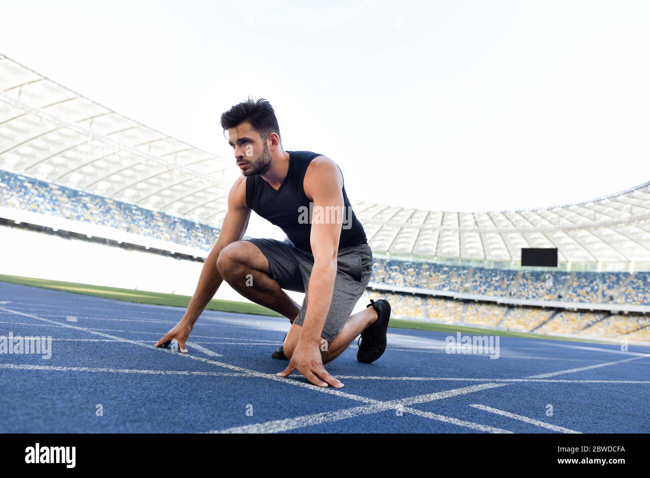 handsome runner in start position on running track at stadium Stock ...