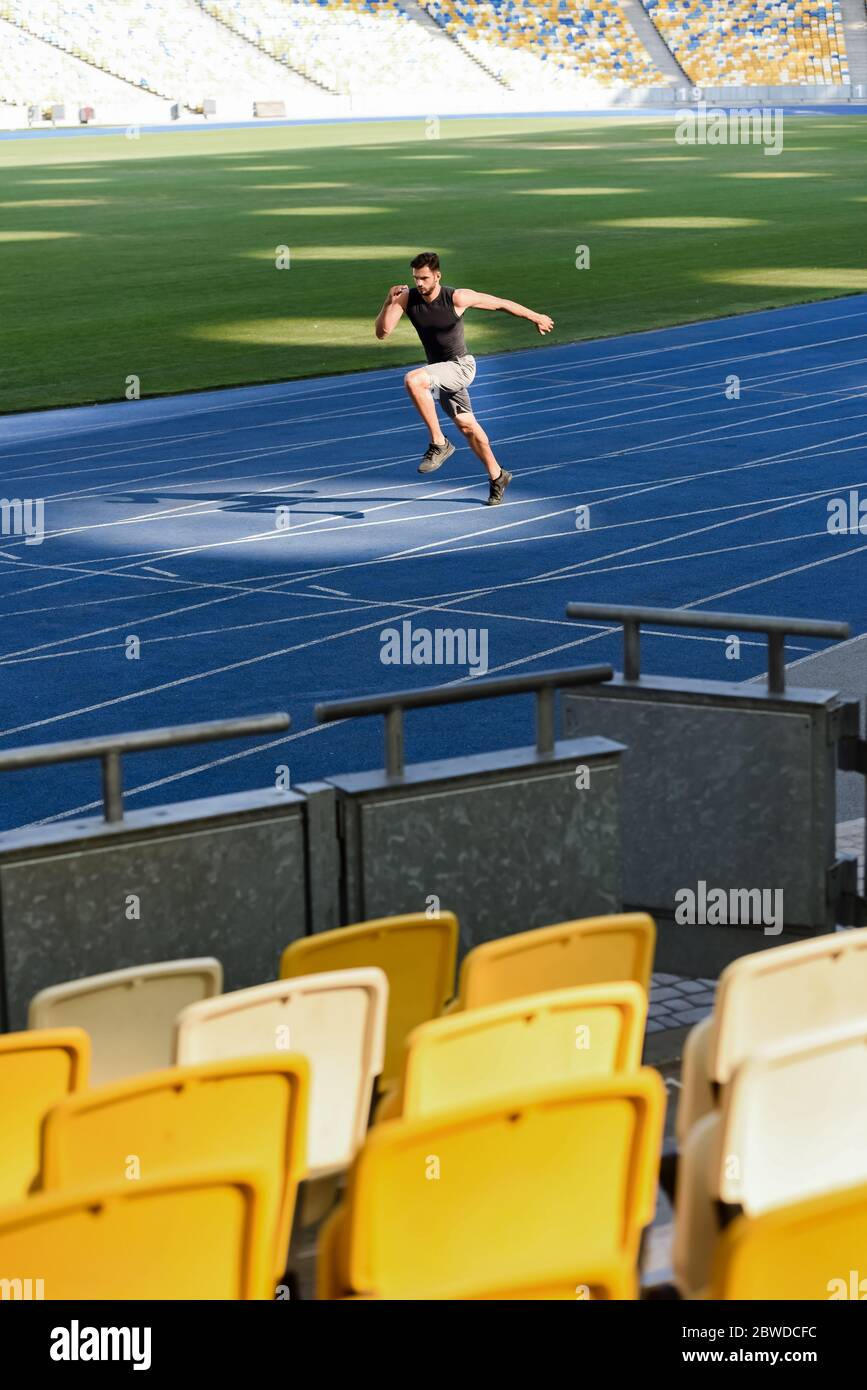selective focus of seats and fast handsome runner exercising on running ...