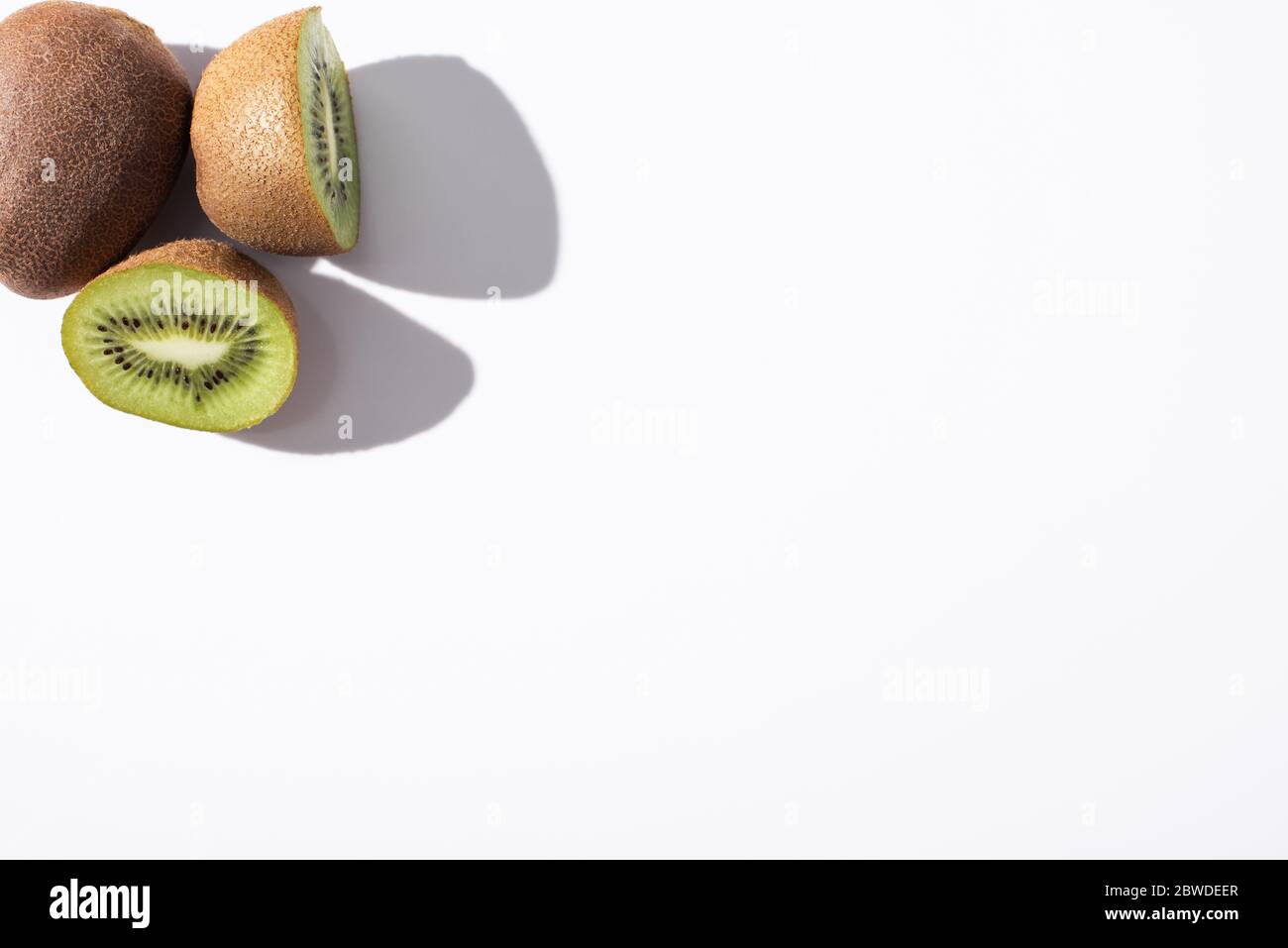 top view of whole kiwi fruit near halves on white with copy space Stock ...