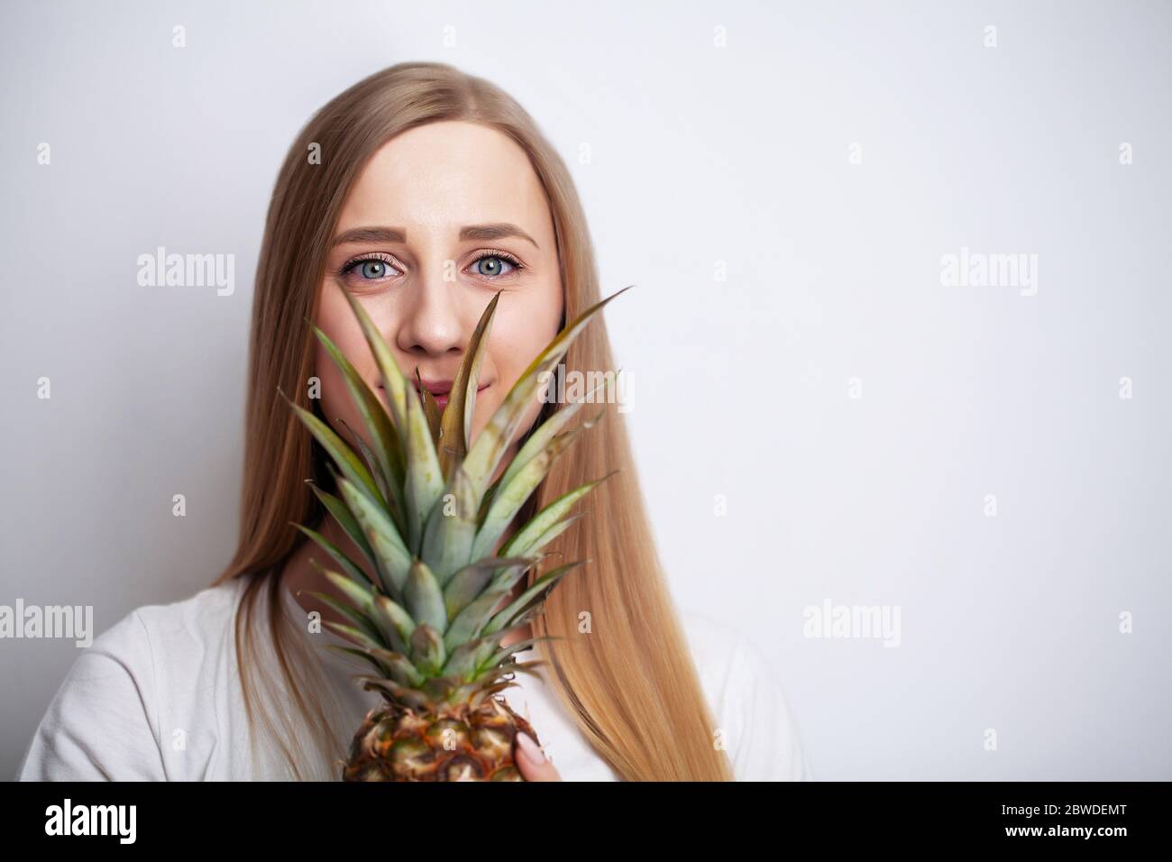 Young woman holding a ripe pineapple near her face Stock Photo - Alamy