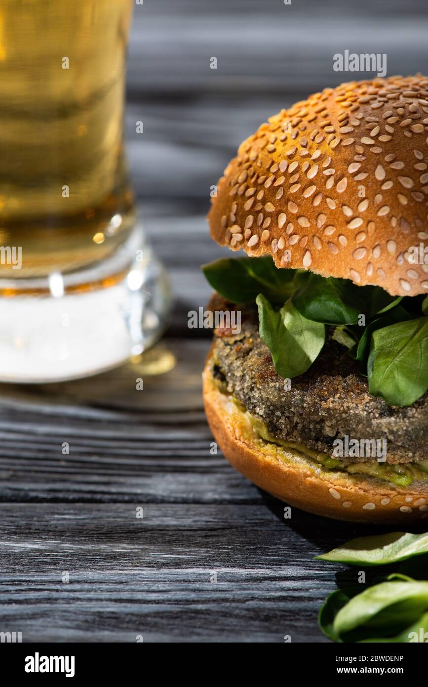 selective focus of tasty vegan burger with microgreens served on wooden ...