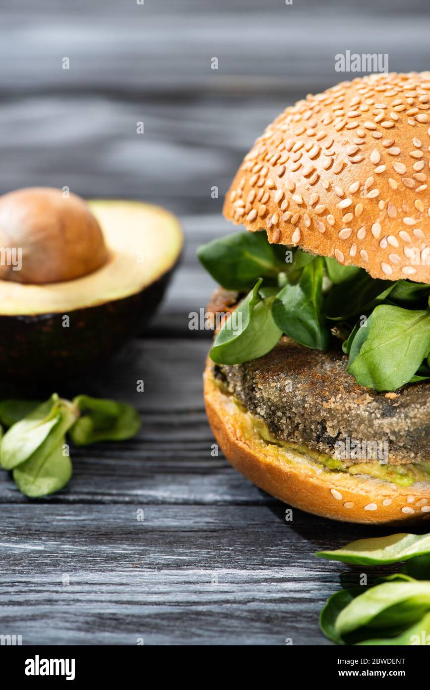 selective focus of tasty vegan burger with microgreens served on wooden ...