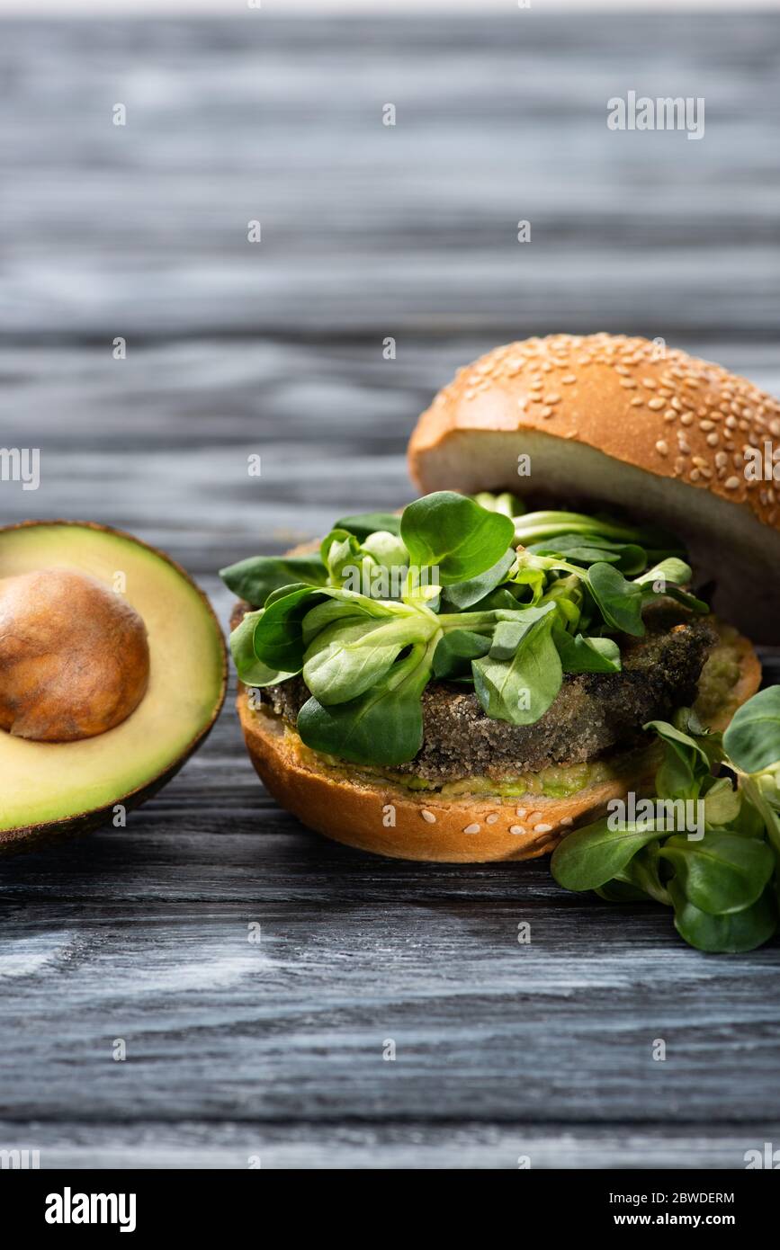 tasty vegan burger with microgreens served on wooden table with avocado ...