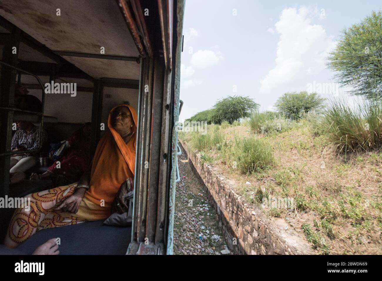 Woman looking out moving train window, second class train. Indian ...