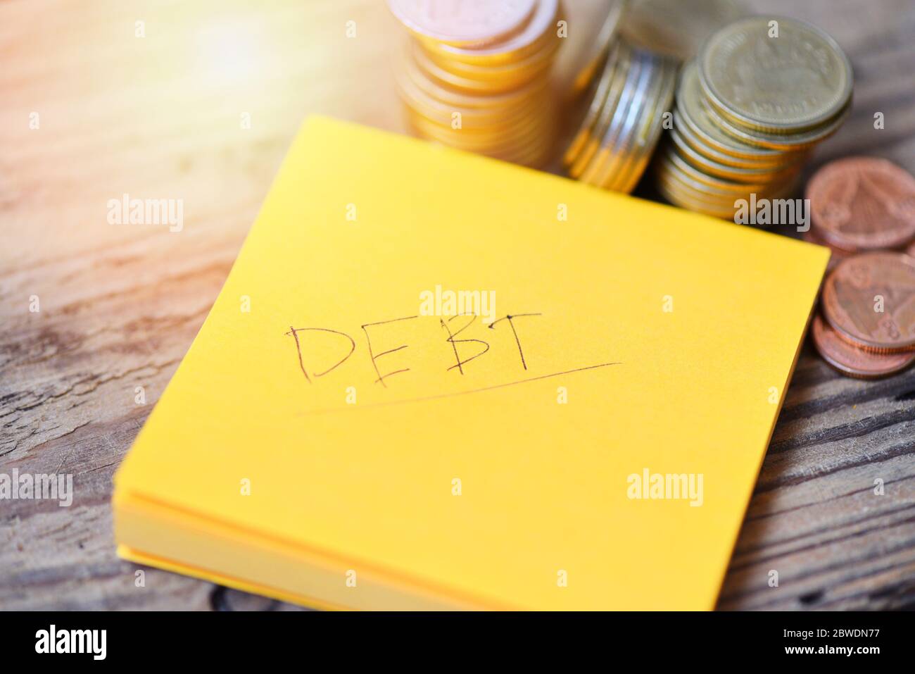 Debt concept with write debt on paper and stacked coins on wooden table ...