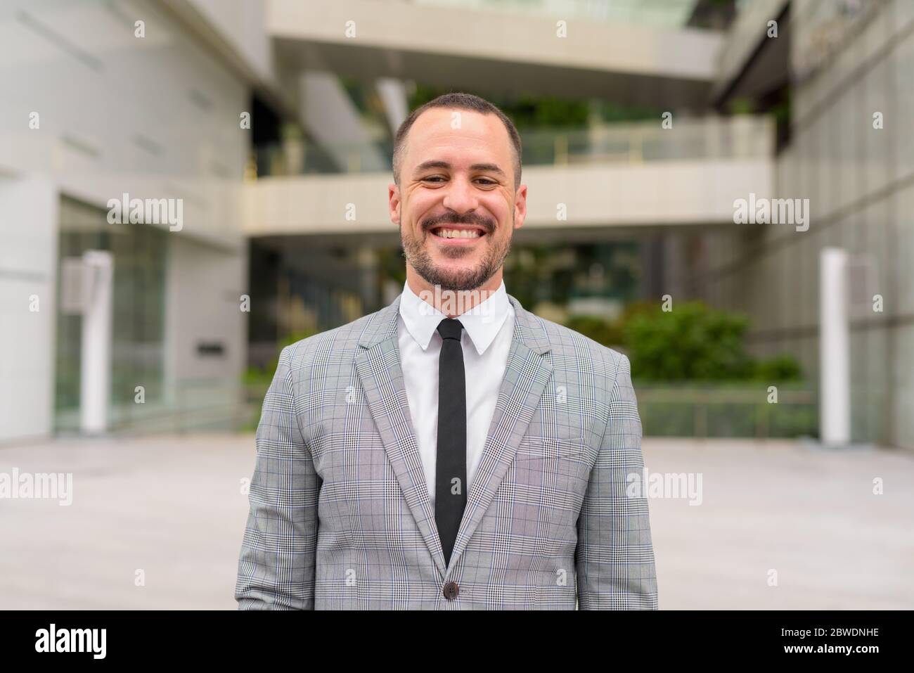 Happy Hispanic bald bearded businessman smiling in the city outdoors ...