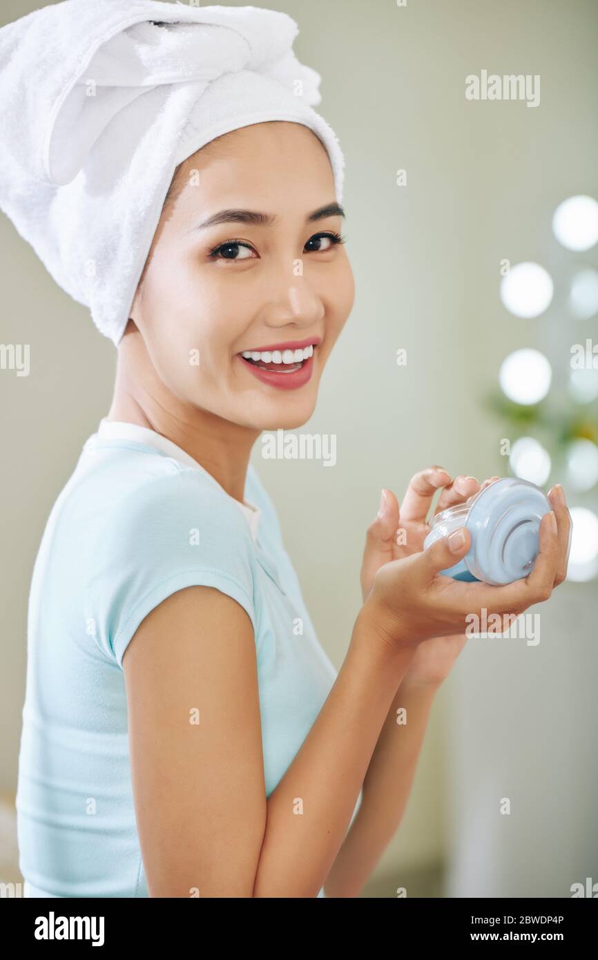 Portrait of young beautiful Asian woman applying moisturizing lotion on ...