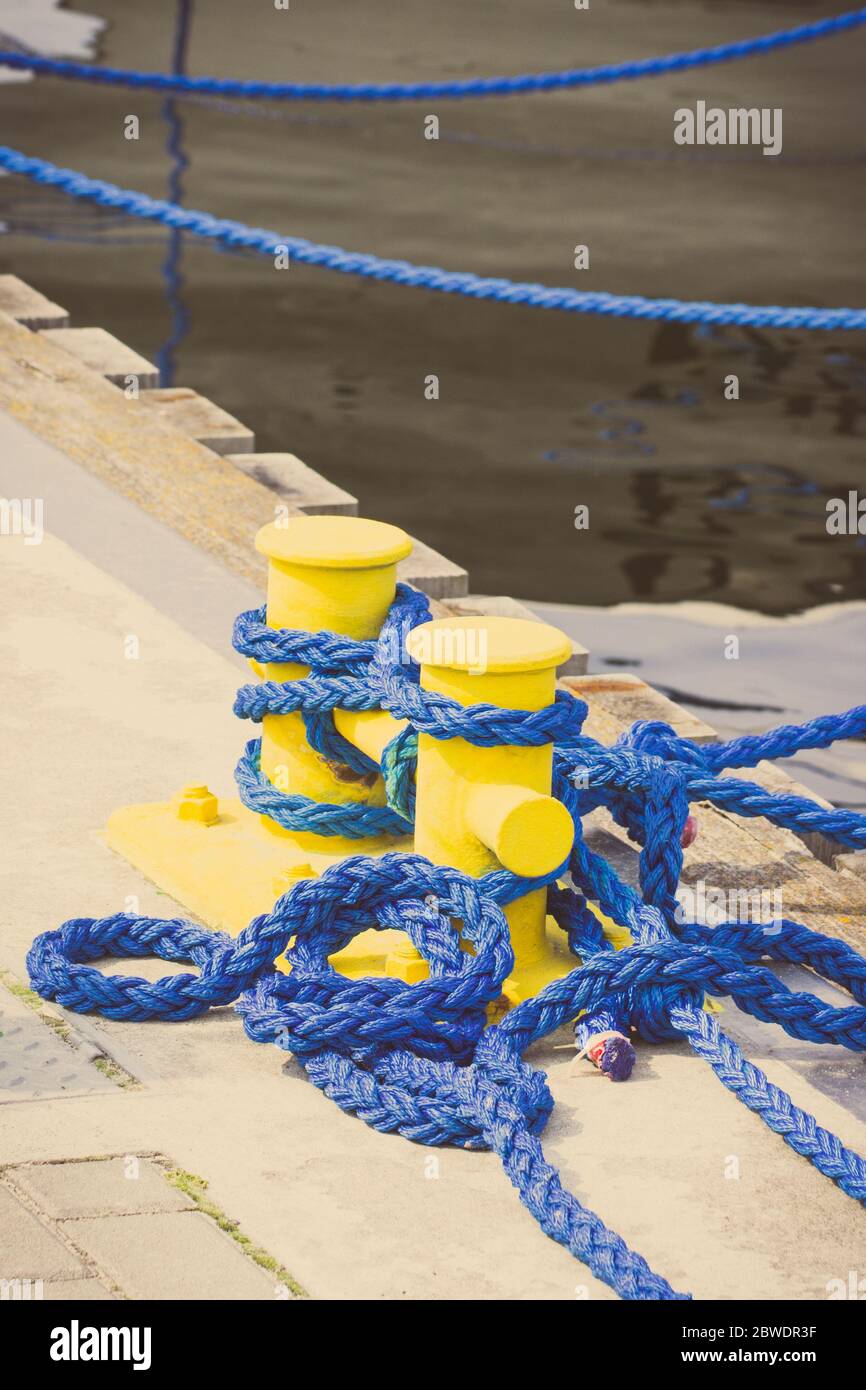 Vintage photo, Blue rope and yellow mooring bollard in port, closeup ...
