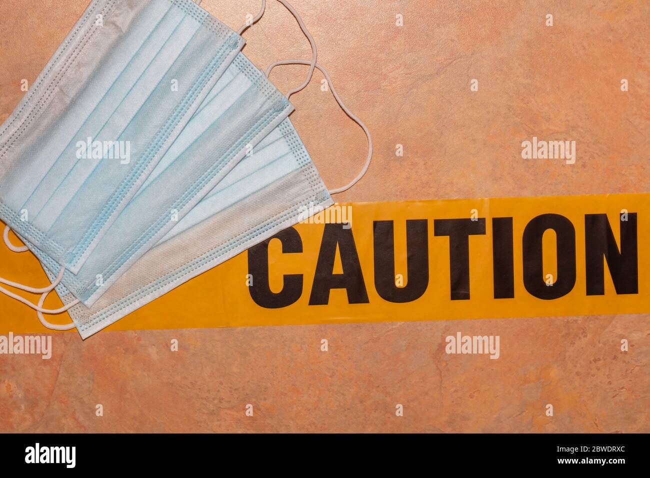 Facial protective masks on top of yellow caution tape. Isolated. Marble ...