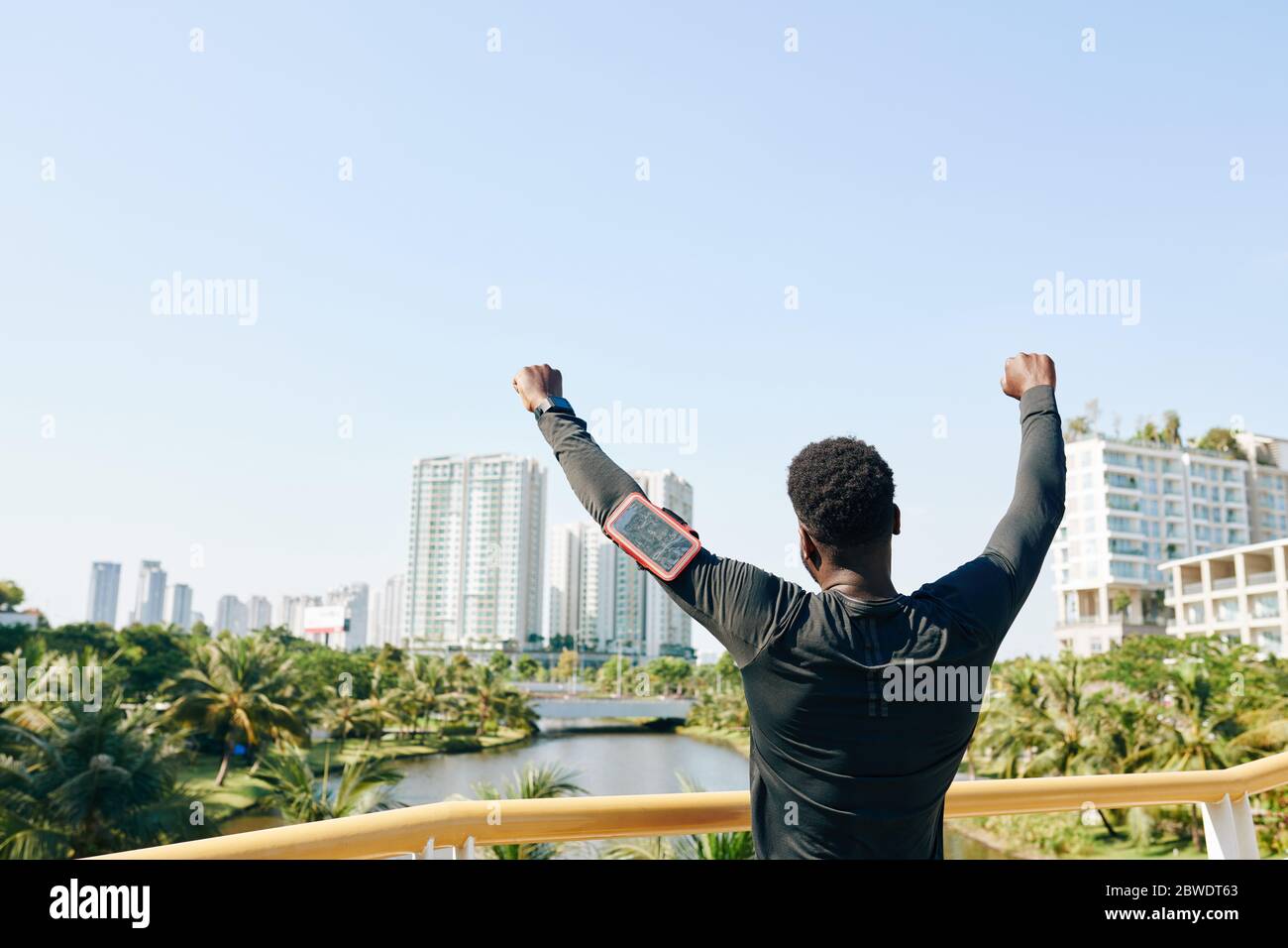 Excited sportsman raising arms and looking at city from highest point ...
