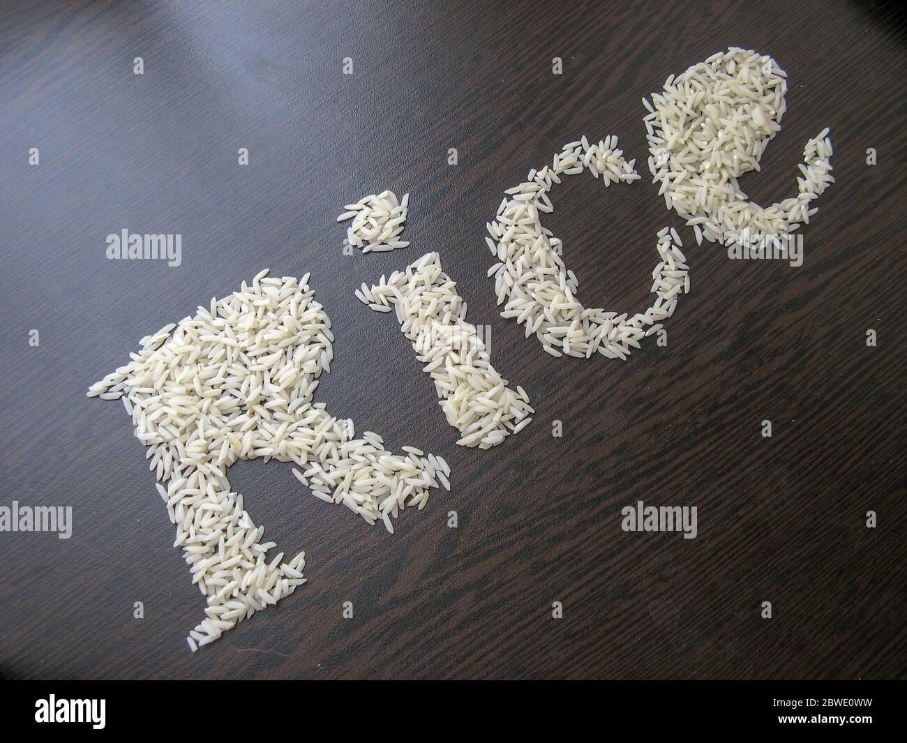 Writing the word Rice with rice seeds on a table with brown wooden ...