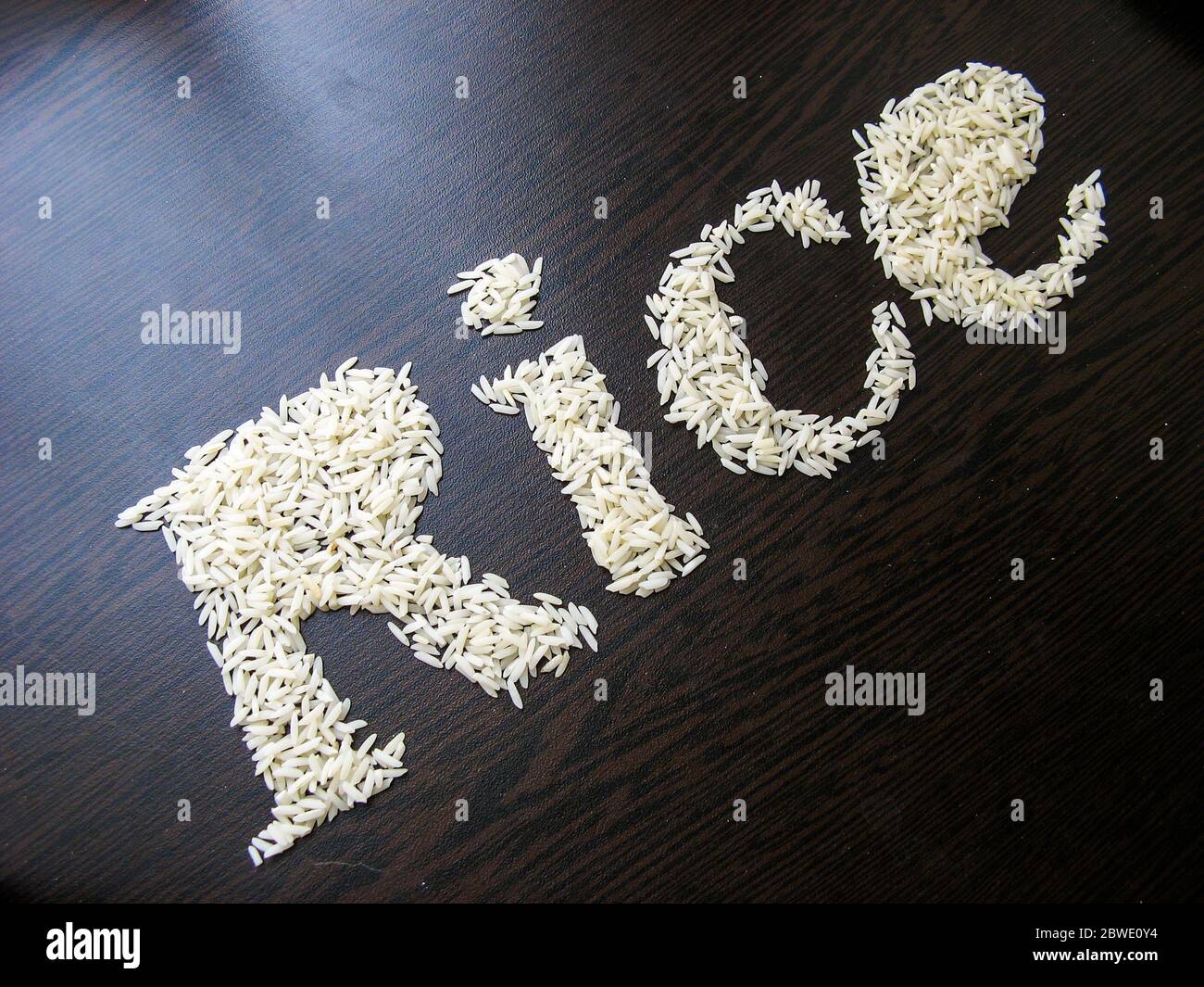 Writing the word Rice with rice seeds on a table with brown wooden ...