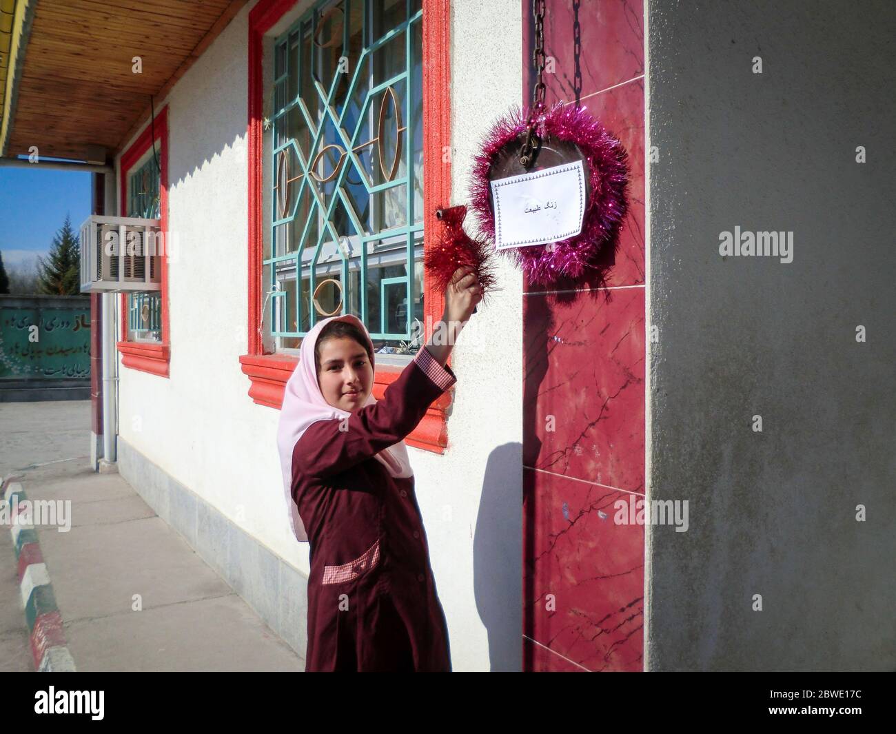 Rasht, Gilan, Iran, 05 05 2019. Muslim girl playing school bell with ...