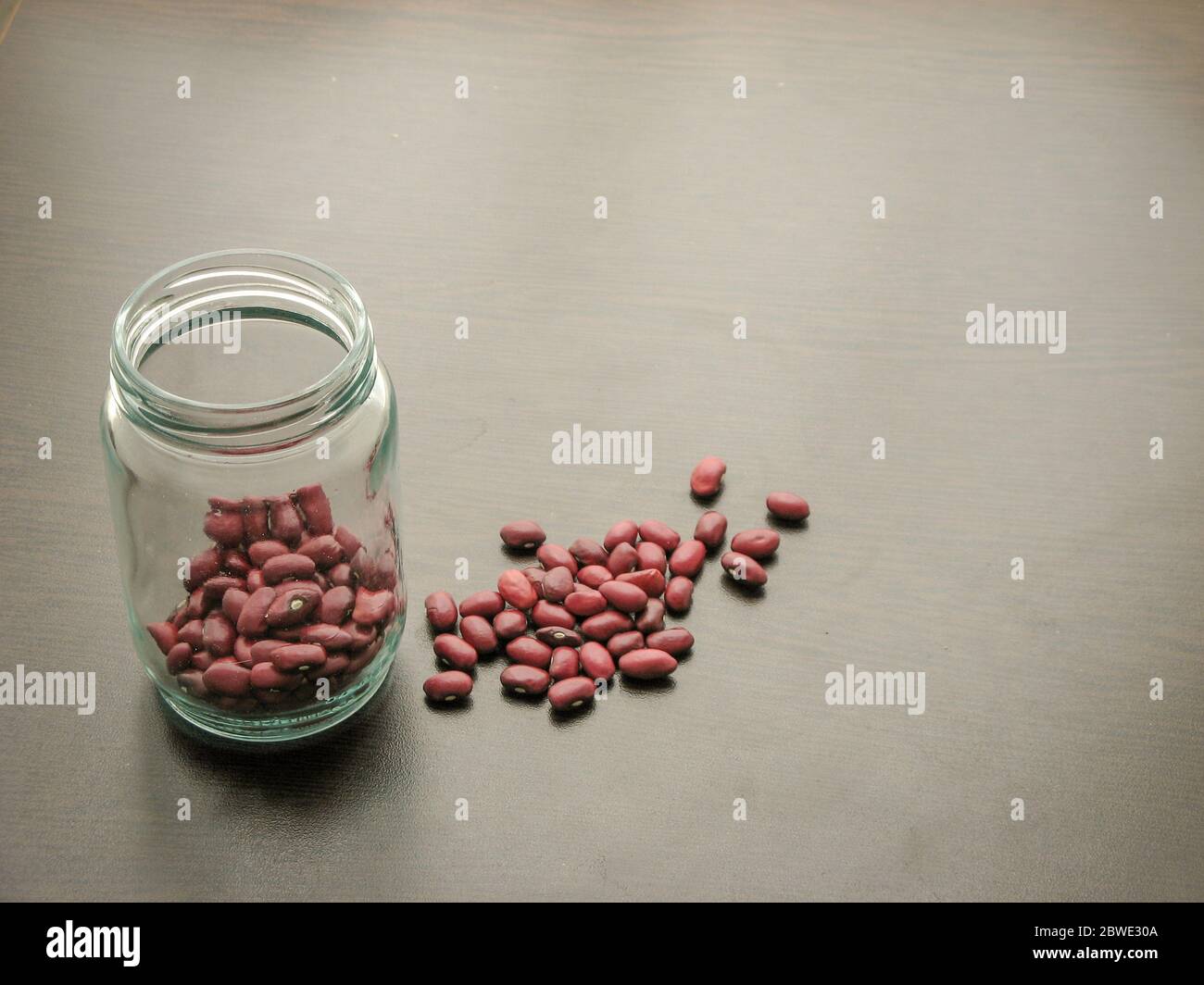Red bean seeds in a glass jar on the wooden table. Red bean seeds in a ...