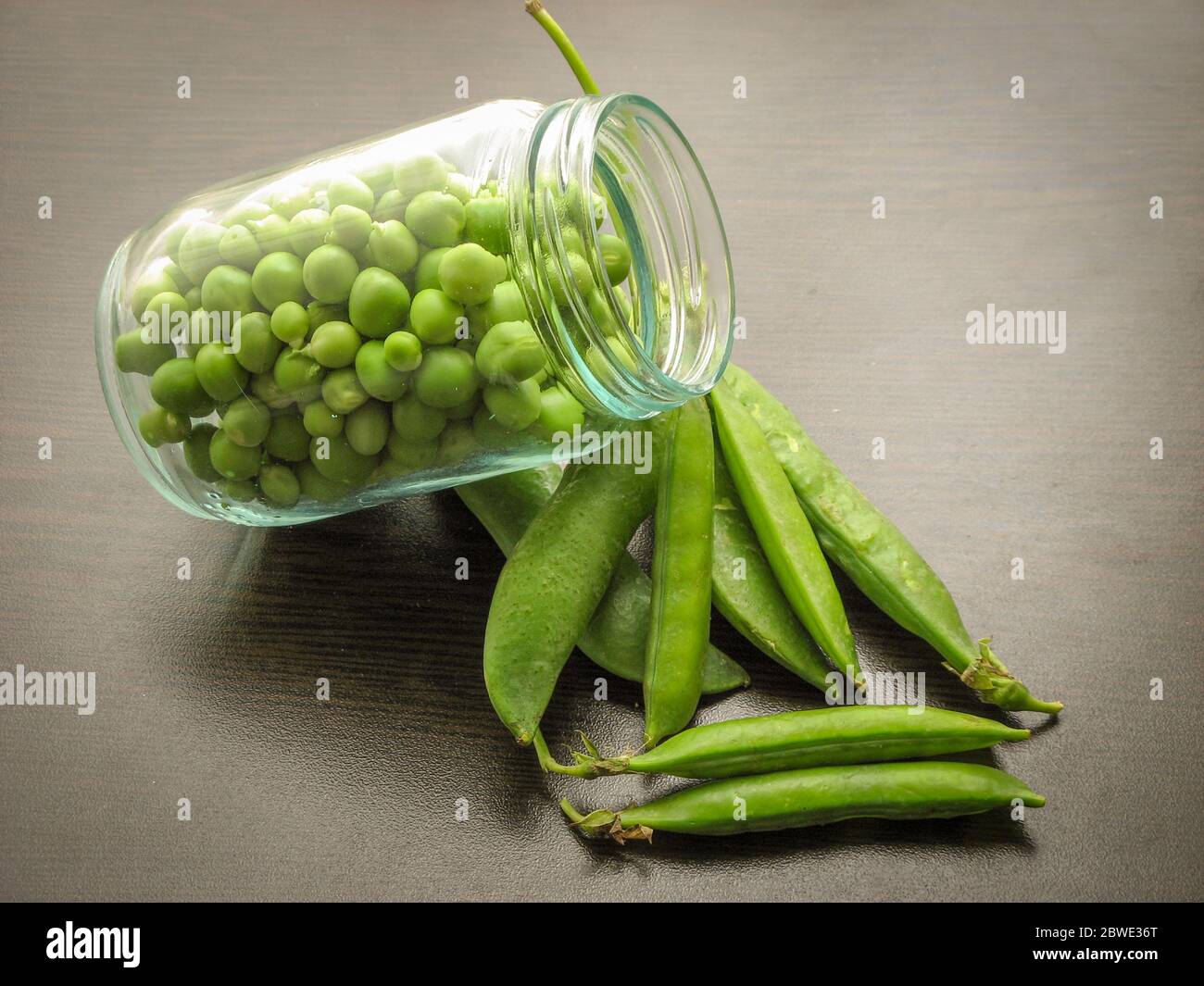 Closeup of fresh green peeled peas (Pisum sativum) in a glass jar on a ...