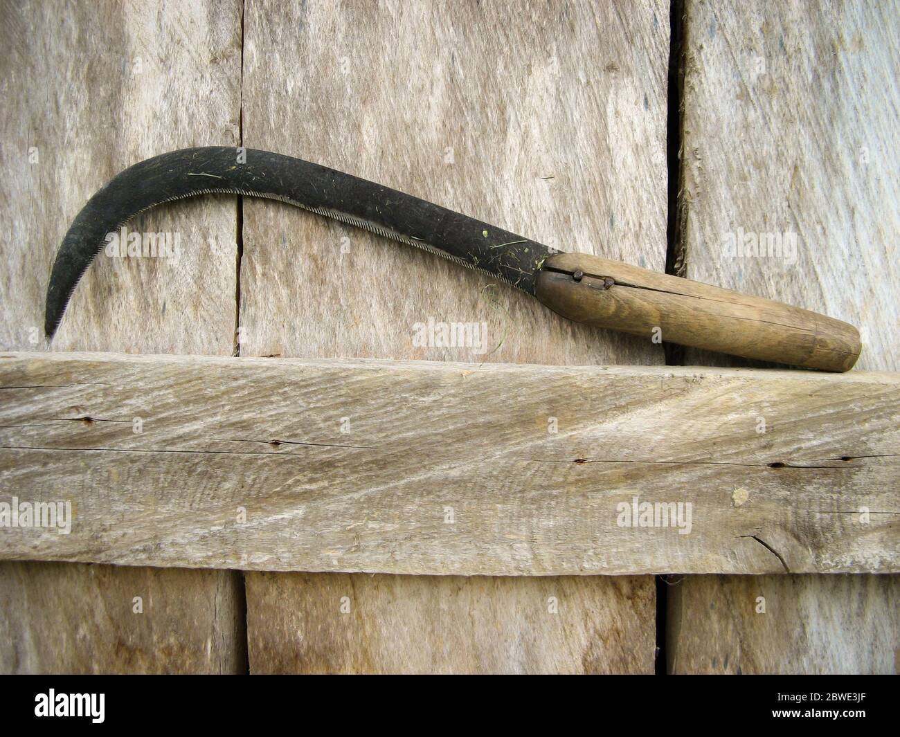 Old agricultural sickle on a wooden plank. Sickle for the harvest of ...