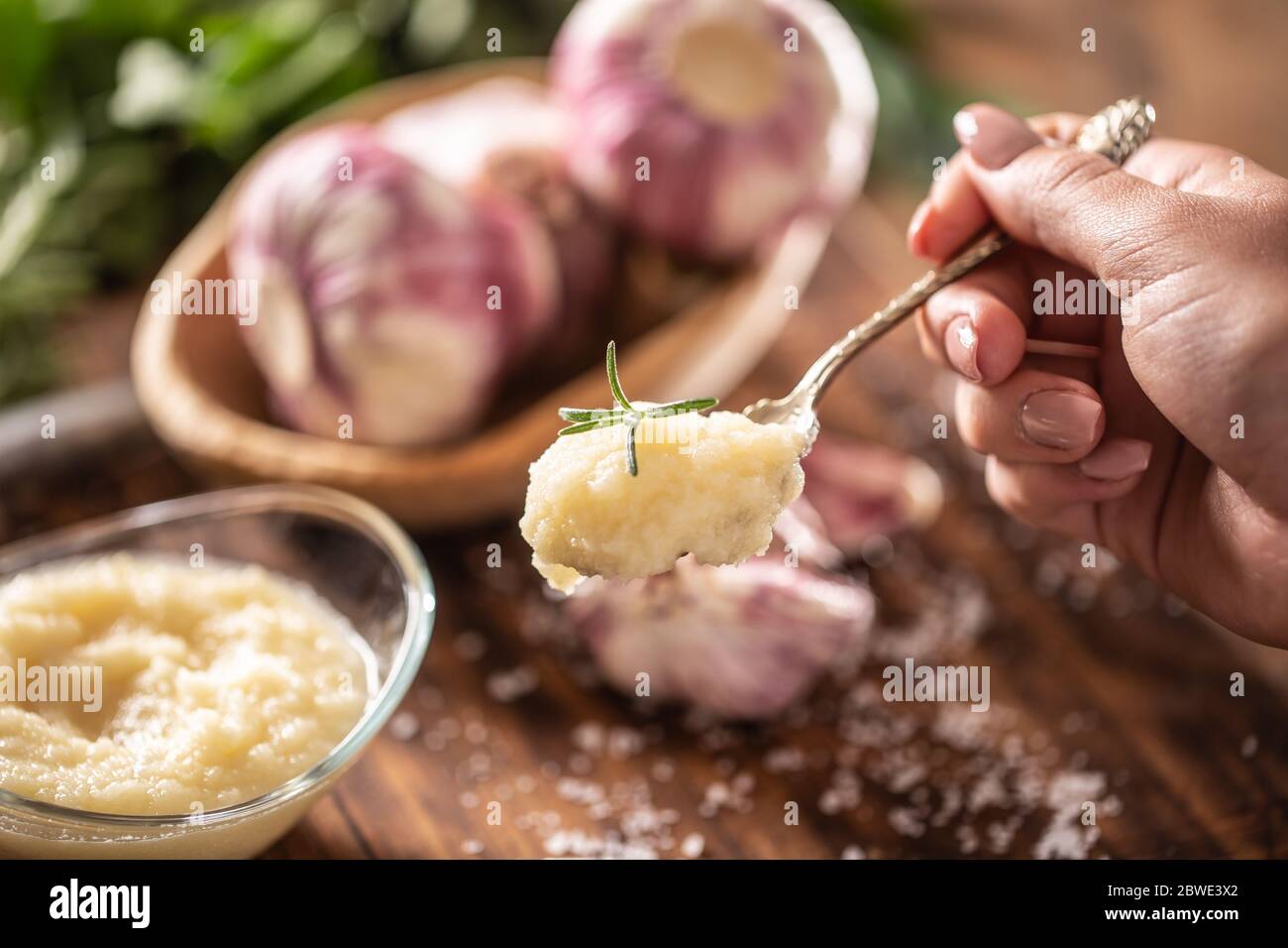 Detail of a teaspoon of garlic paste with fresh garlic in the ...