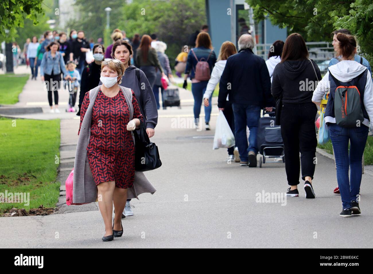Crowd of people with and without medical masks walking on a street in a ...