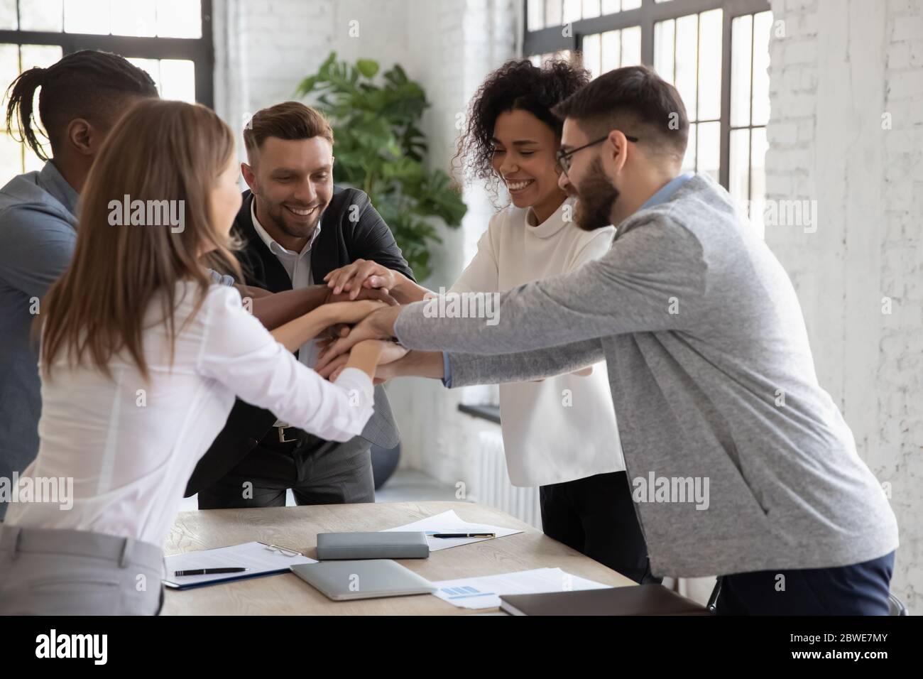 Successful diverse employees stacking hands, engaged in team building ...