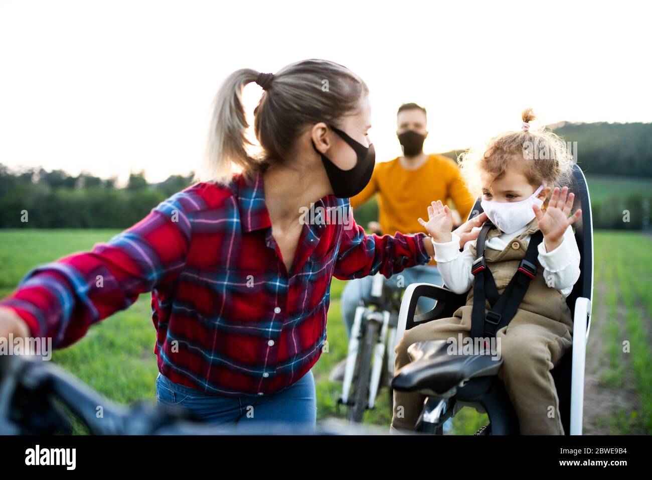 Family with two small children on cycling trip, wearing face masks ...