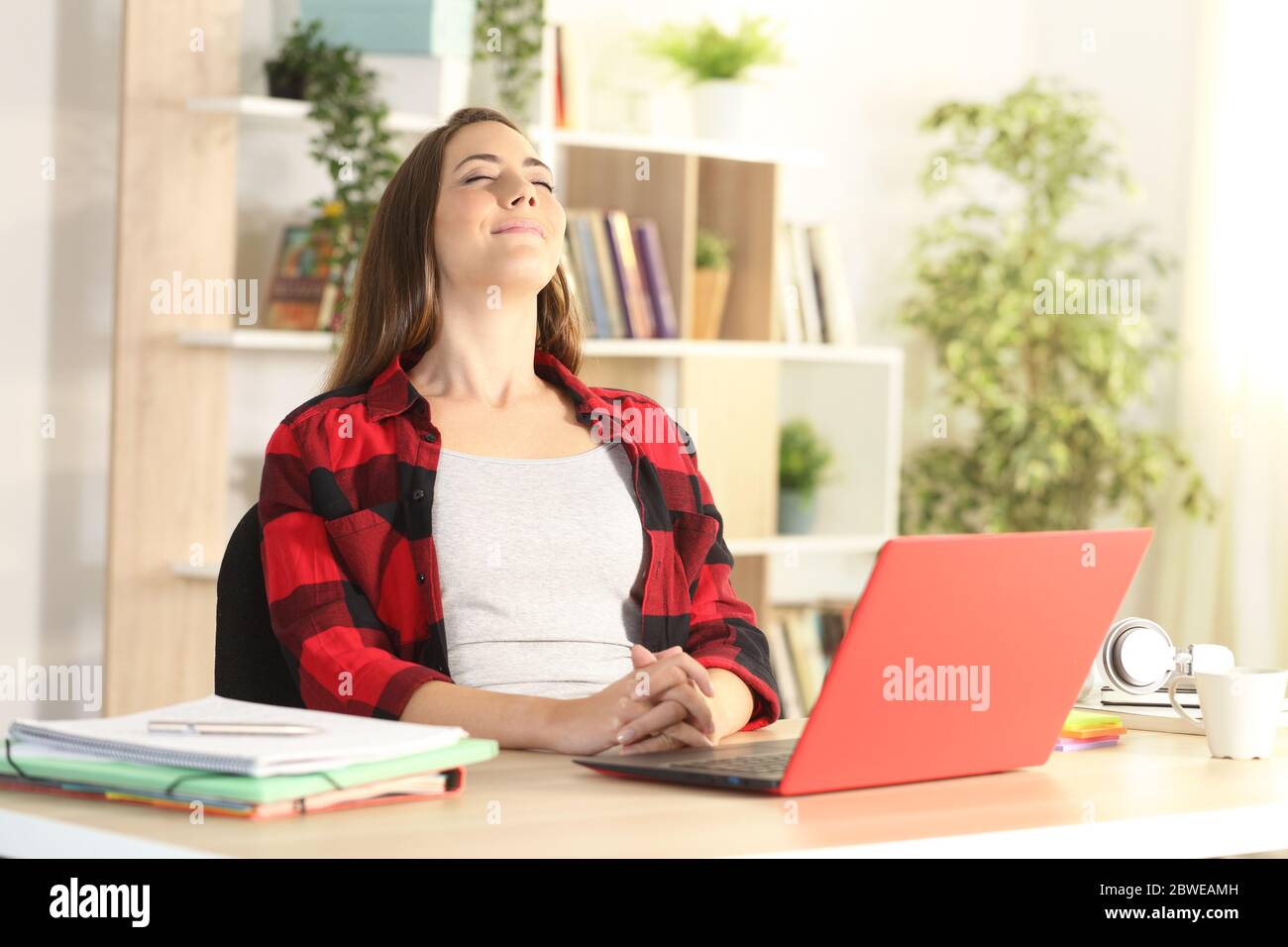 Relaxed student woman with red laptop breathing fresh air sitting on a ...