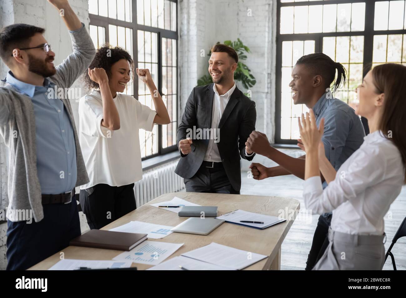 Excited diverse employees celebrating great teamwork result at meeting ...