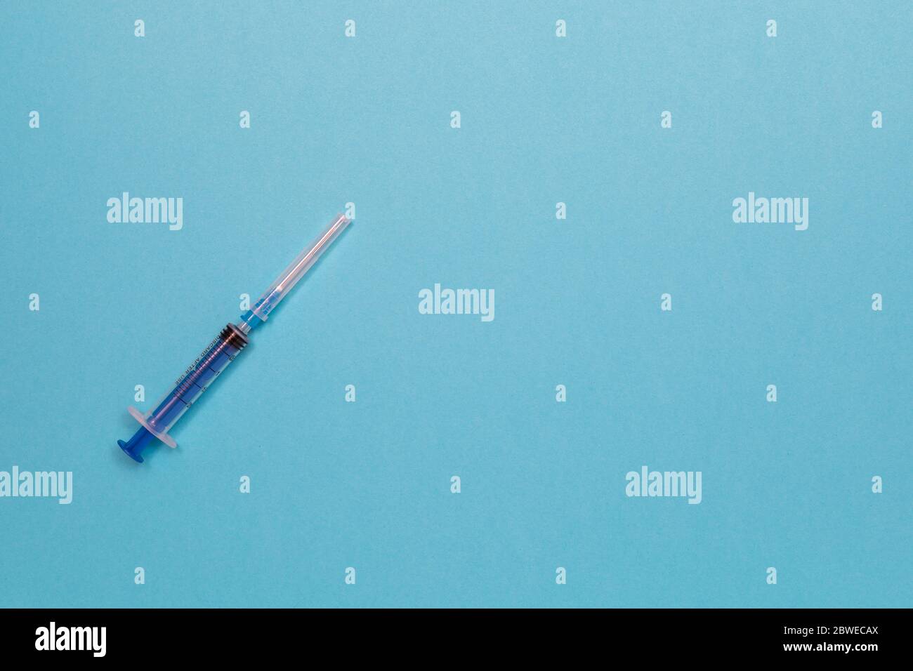 Syringe for injection with a needle on a blue background. Top view with ...