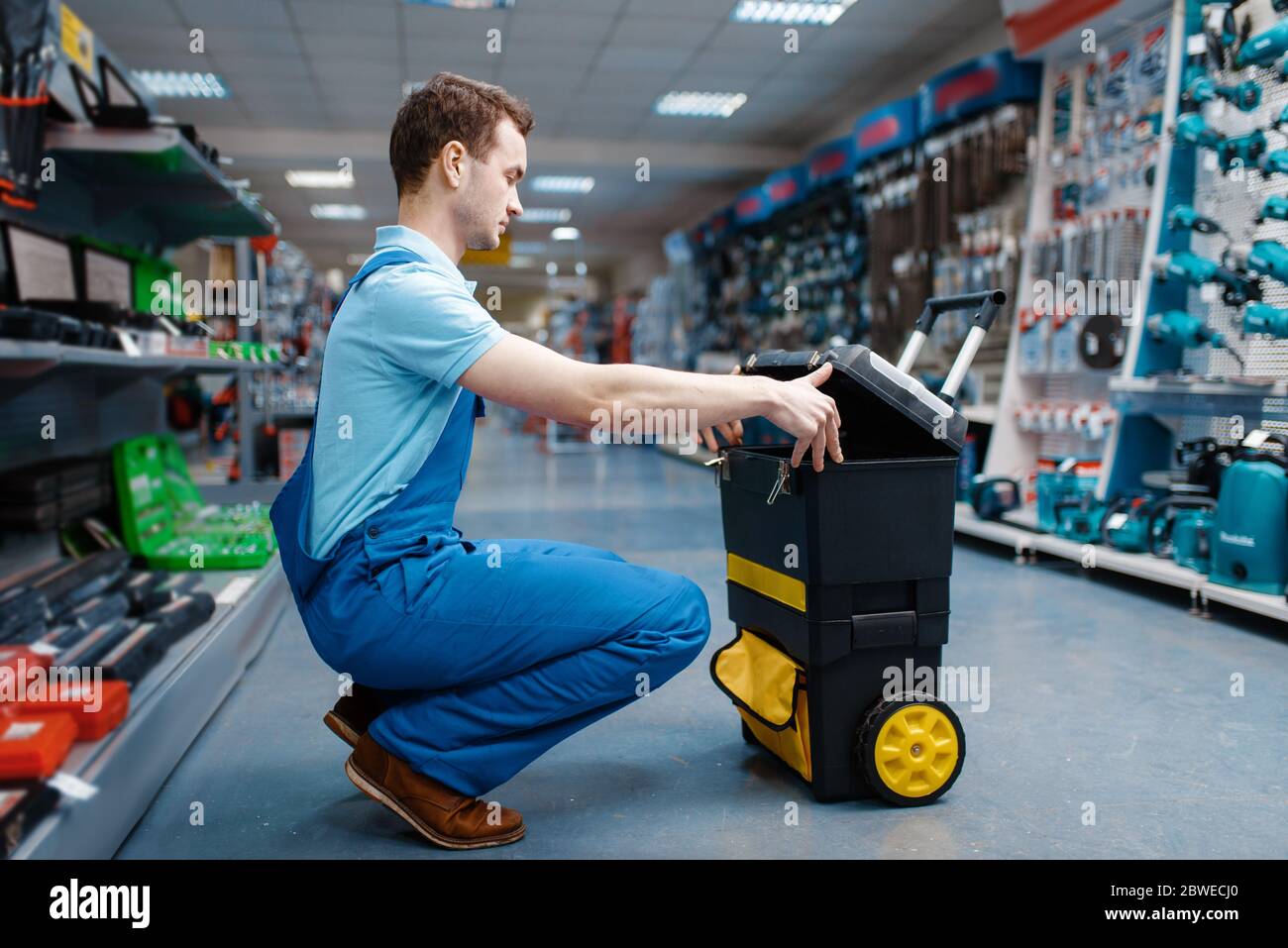 Male worker holds toolbox on wheels in tool store Stock Photo - Alamy
