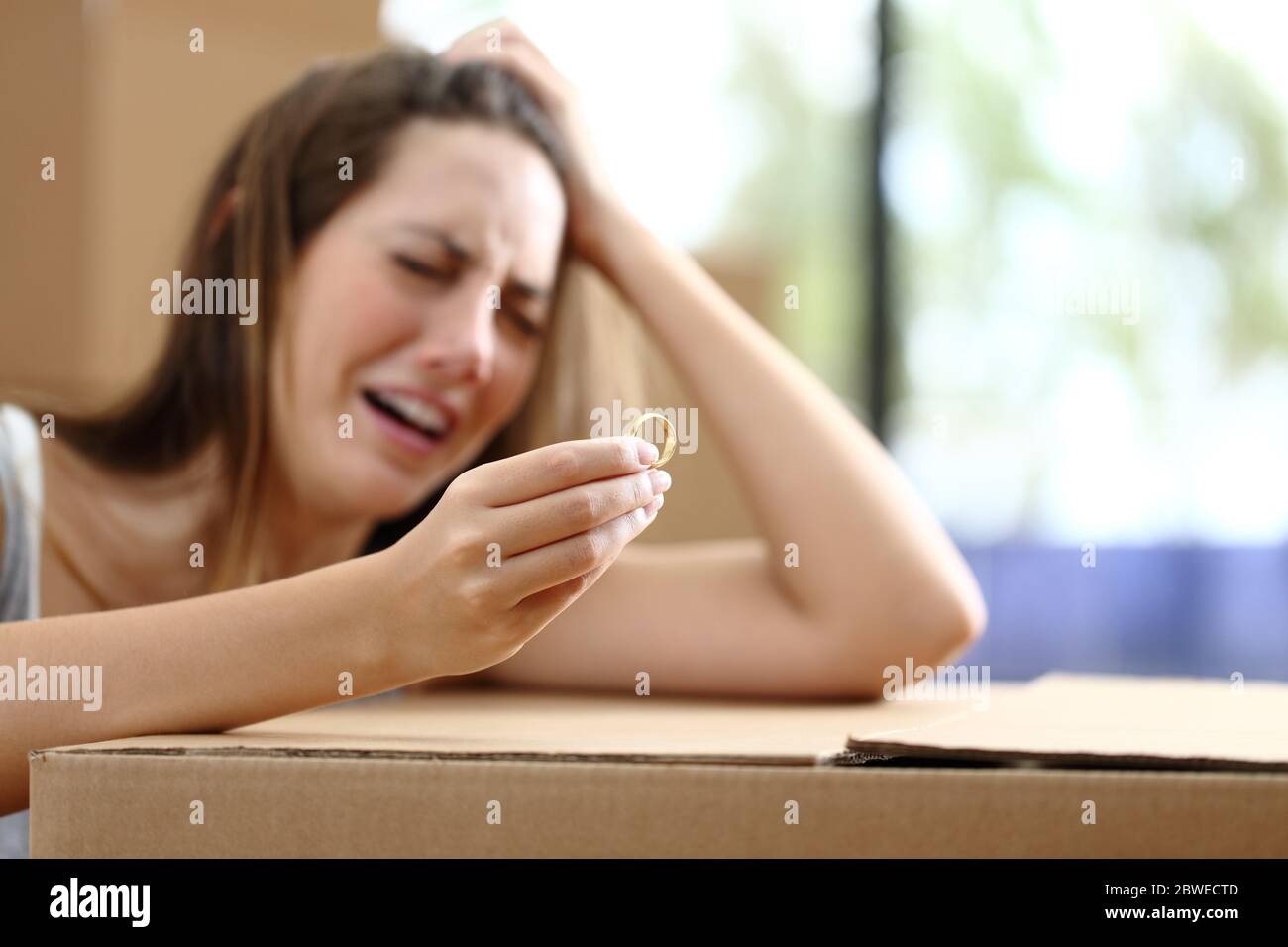 Sad wife complaining moving home after divorce holding wedding ring ...