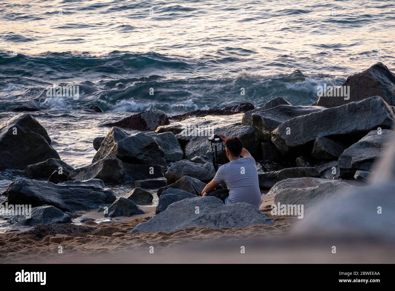 Photographer on the beach setting up the camera and waiting for a good ...