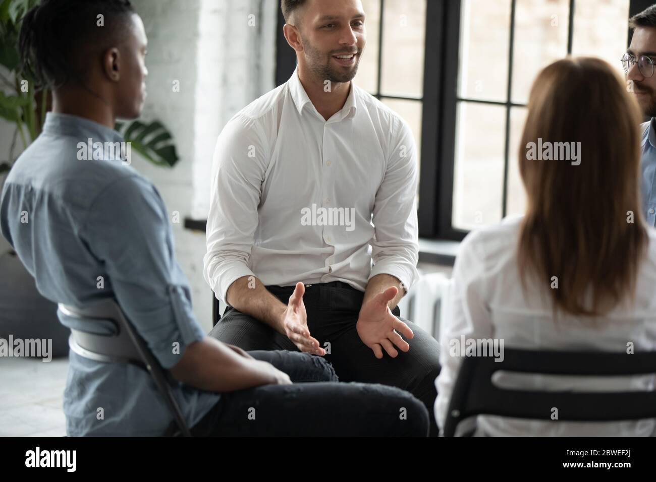 Smiling confident psychologist speaking at group therapy session Stock ...