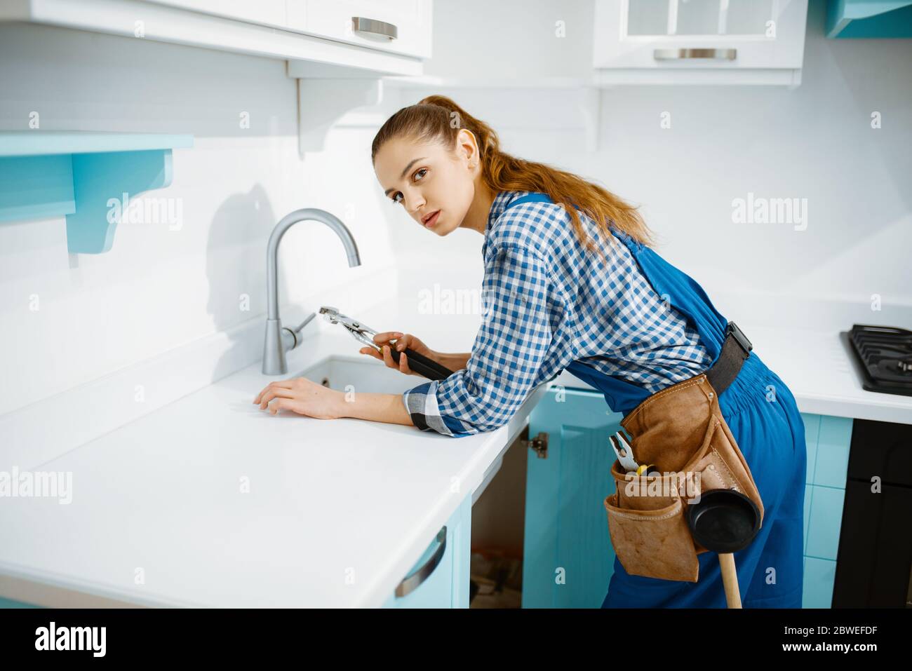 Cute female plumber in uniform fixing faucet Stock Photo - Alamy