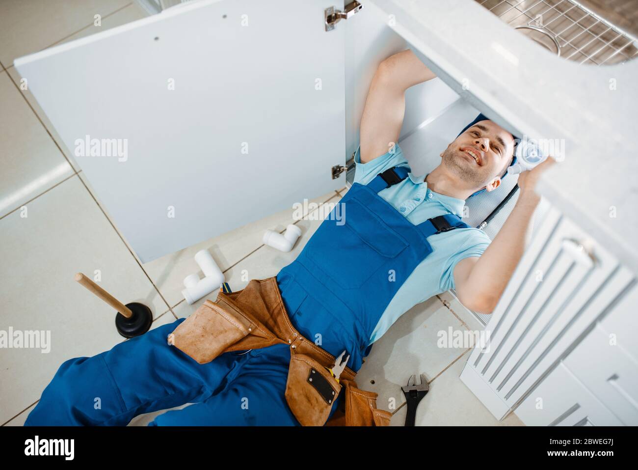 Plumber in uniform installing drain pipe, top view Stock Photo - Alamy