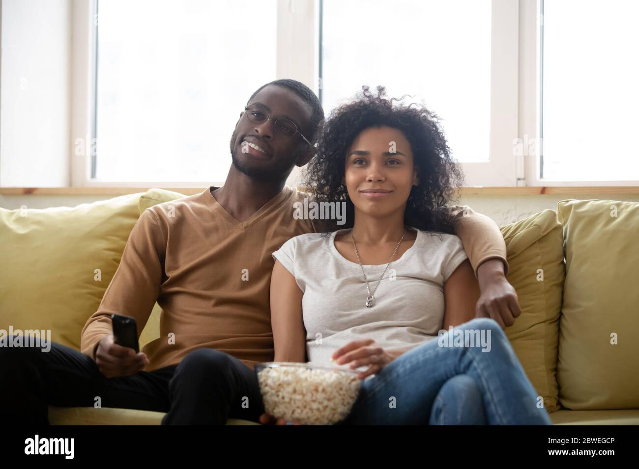 Couple sitting on couch eating popcorn watching movies on TV Stock ...