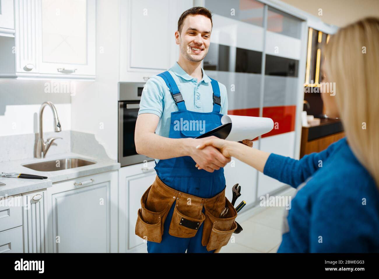 Male plumber and female customer in the kitchen Stock Photo - Alamy