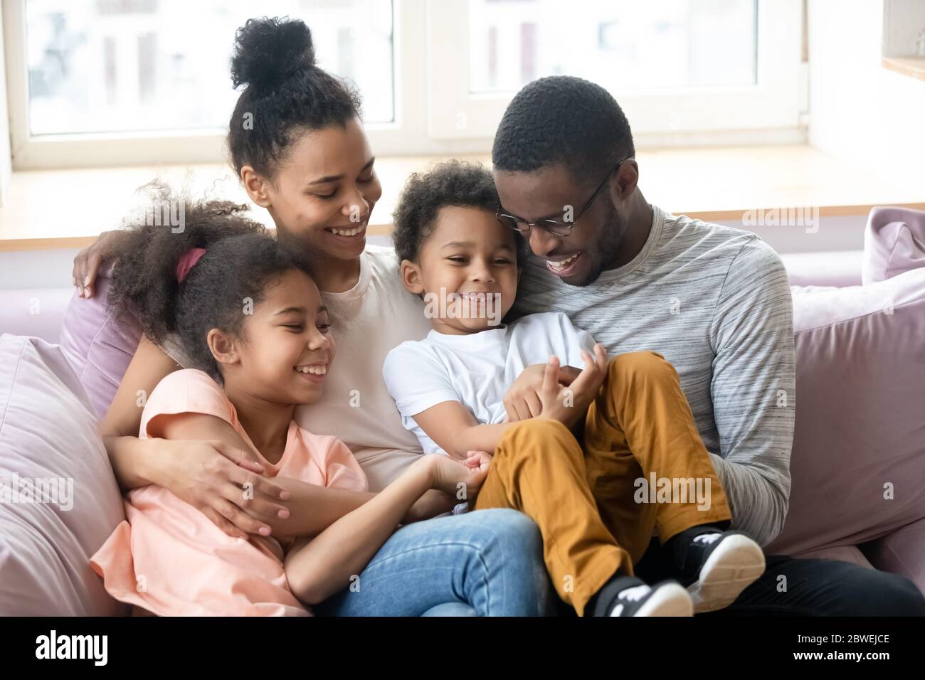 African parents with kids having fun sitting on couch indoors Stock ...