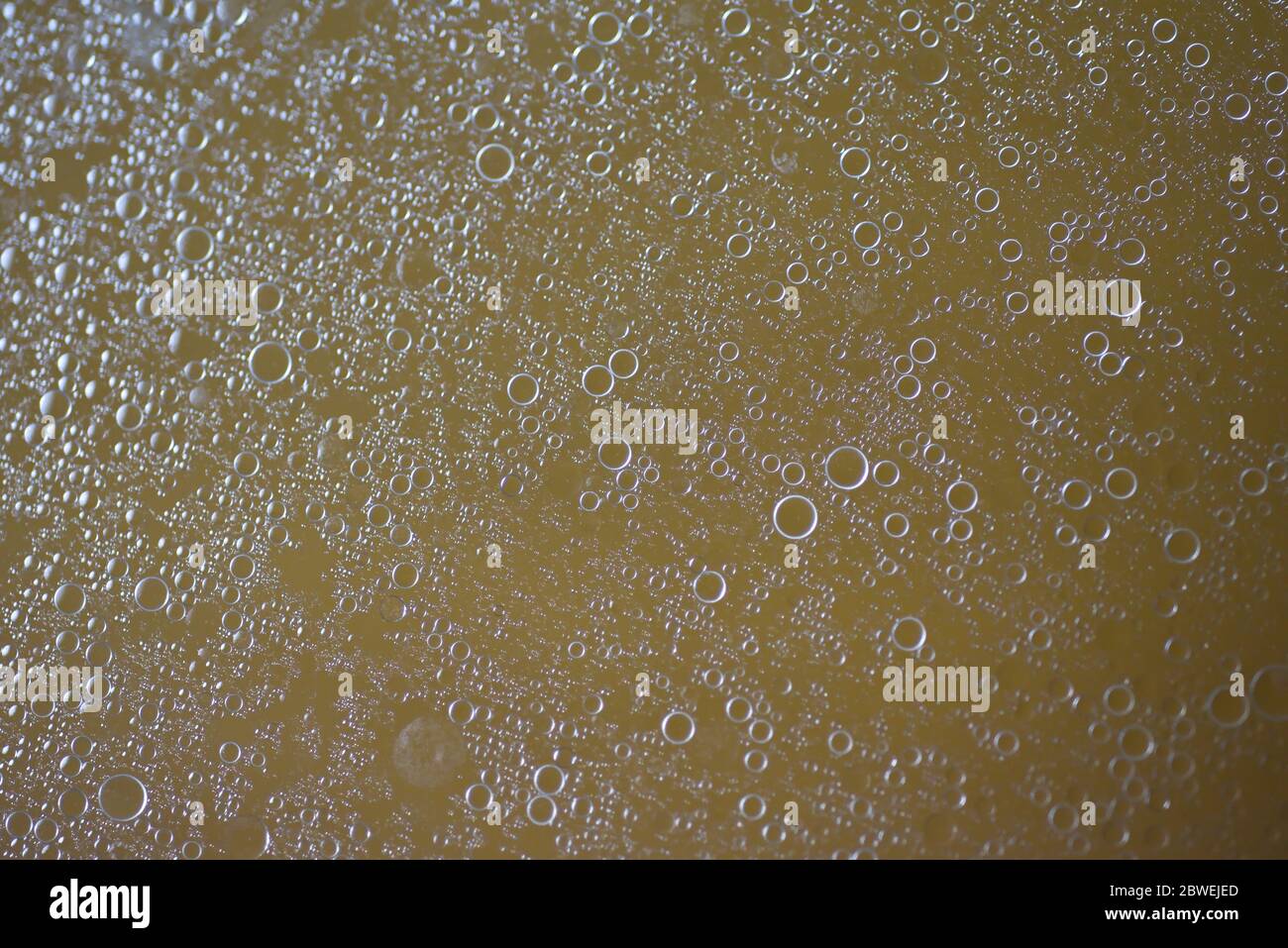 Oil drop over the water golden background Stock Photo - Alamy