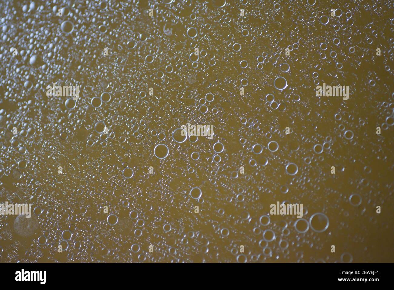 Oil drop over the water golden background Stock Photo - Alamy