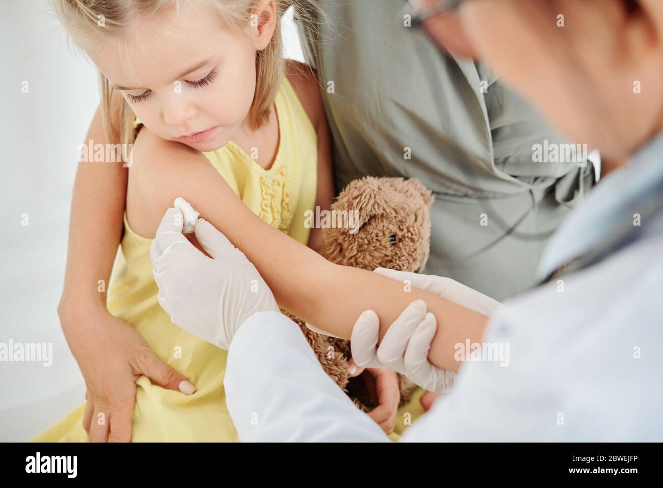 Pediatrician cleaning site selected for injection with alcohol swab ...