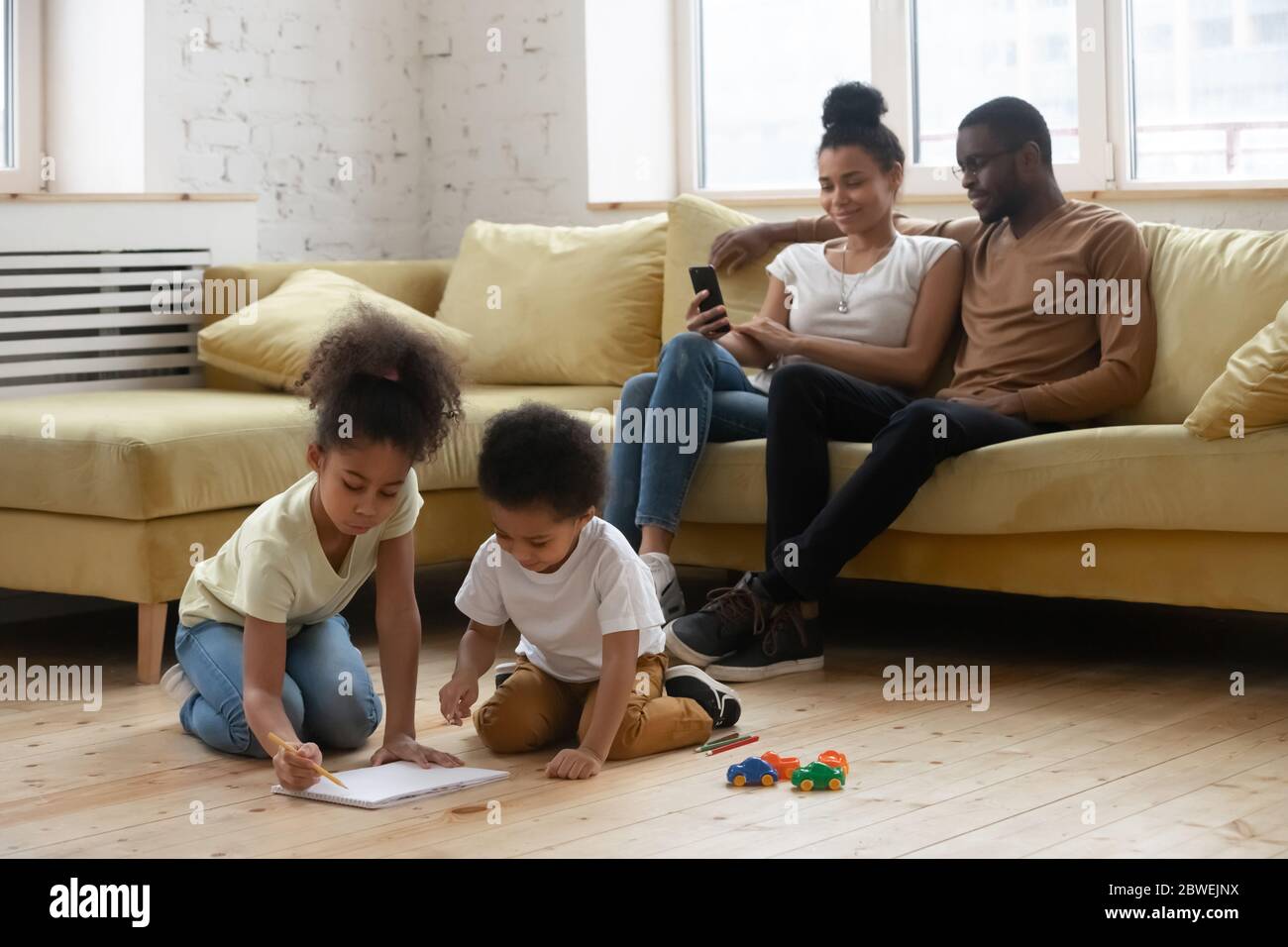 Kids drawing sitting on warm floor parents resting on couch Stock Photo ...