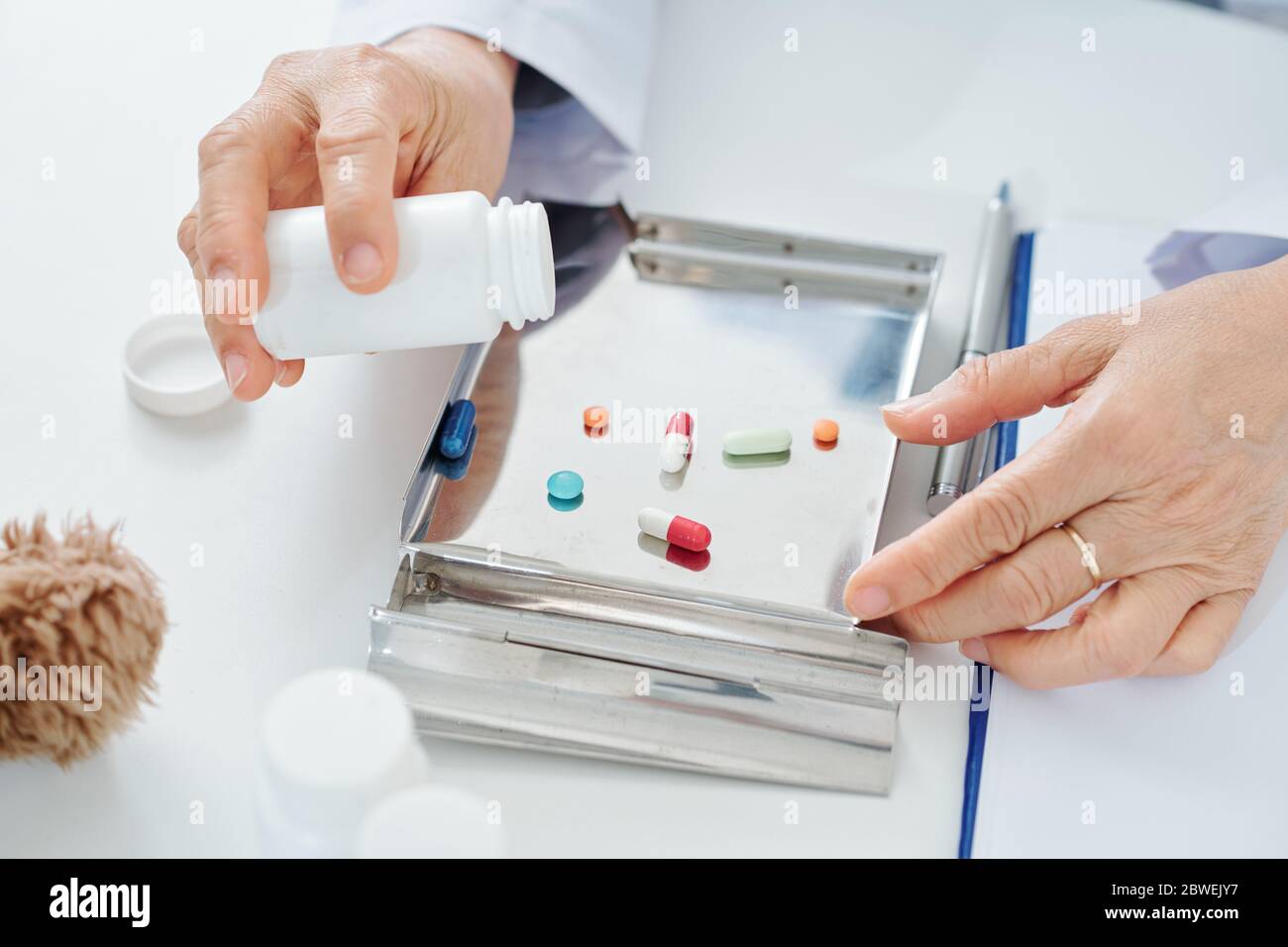 General practitioner putting pills and tablets in stainless steel tray ...
