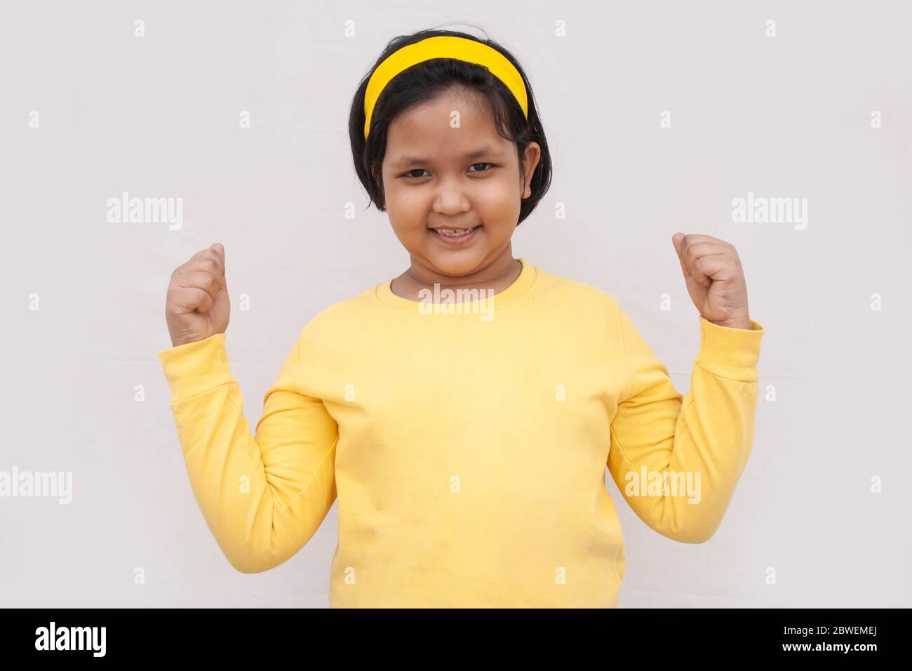 Portrait Of Smiling Girl Flexing Muscles Against grey Background Stock ...