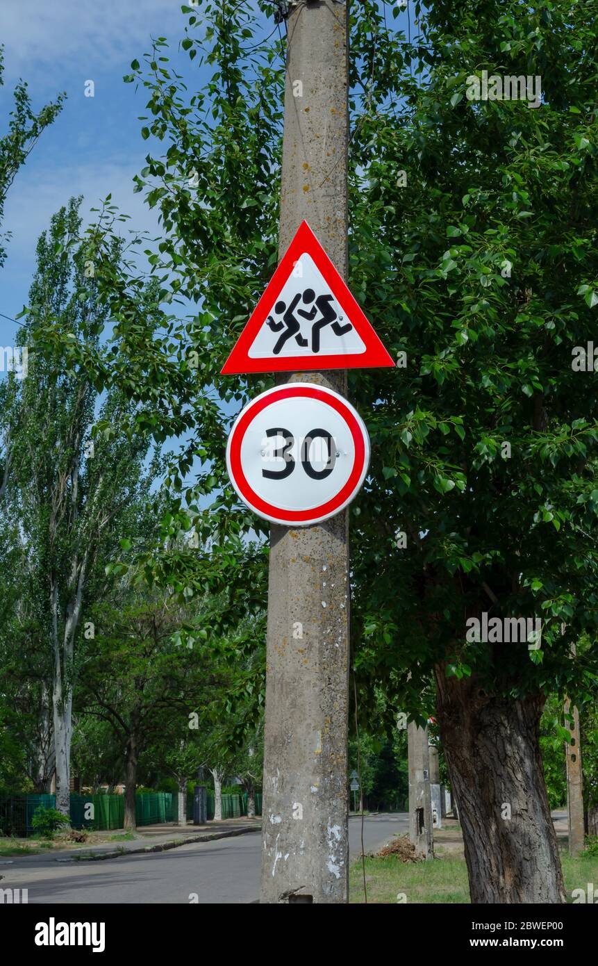 Road sign speed limit 30 and caution children on a green city street ...