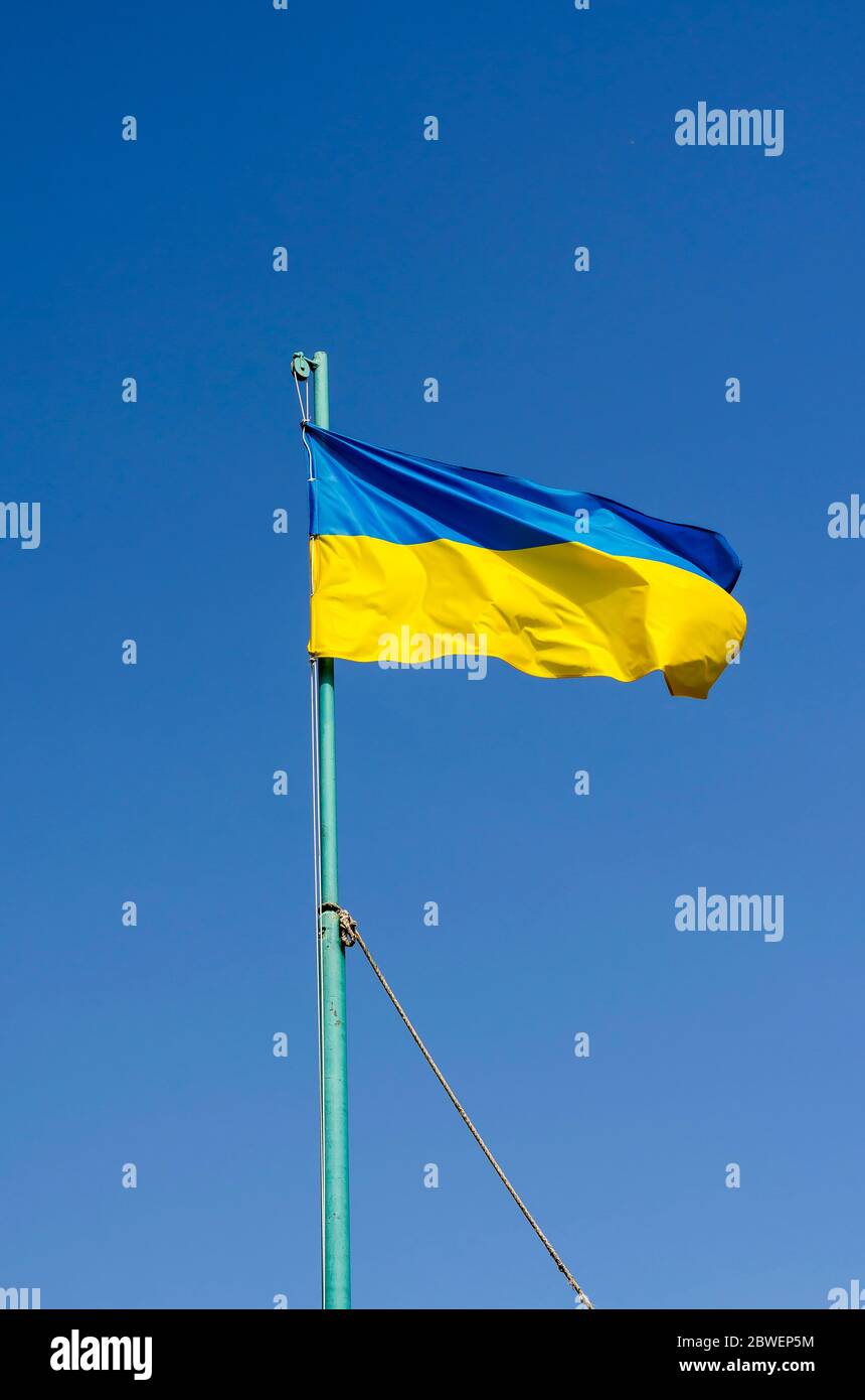 Ukrainian flag flying on a flagpole in against the blue sky. State ...