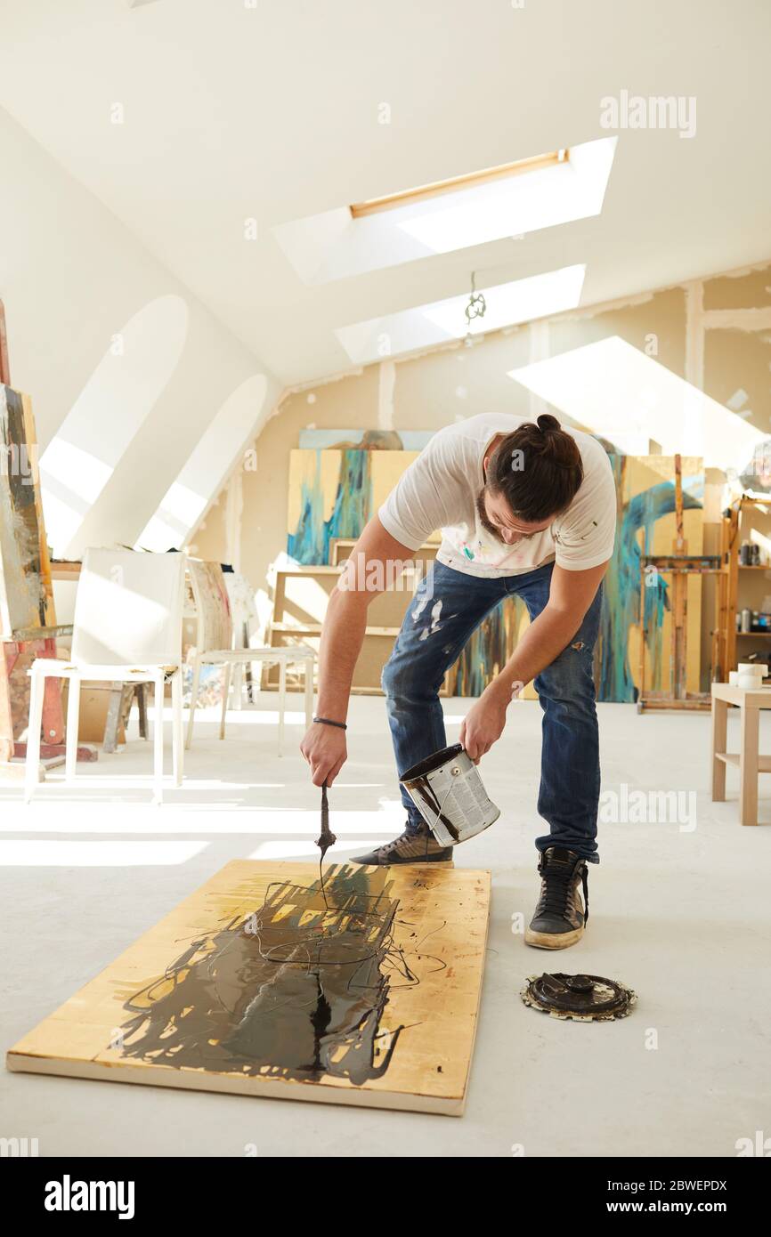 Vertical full length portrait of contemporary male artist splattering ...